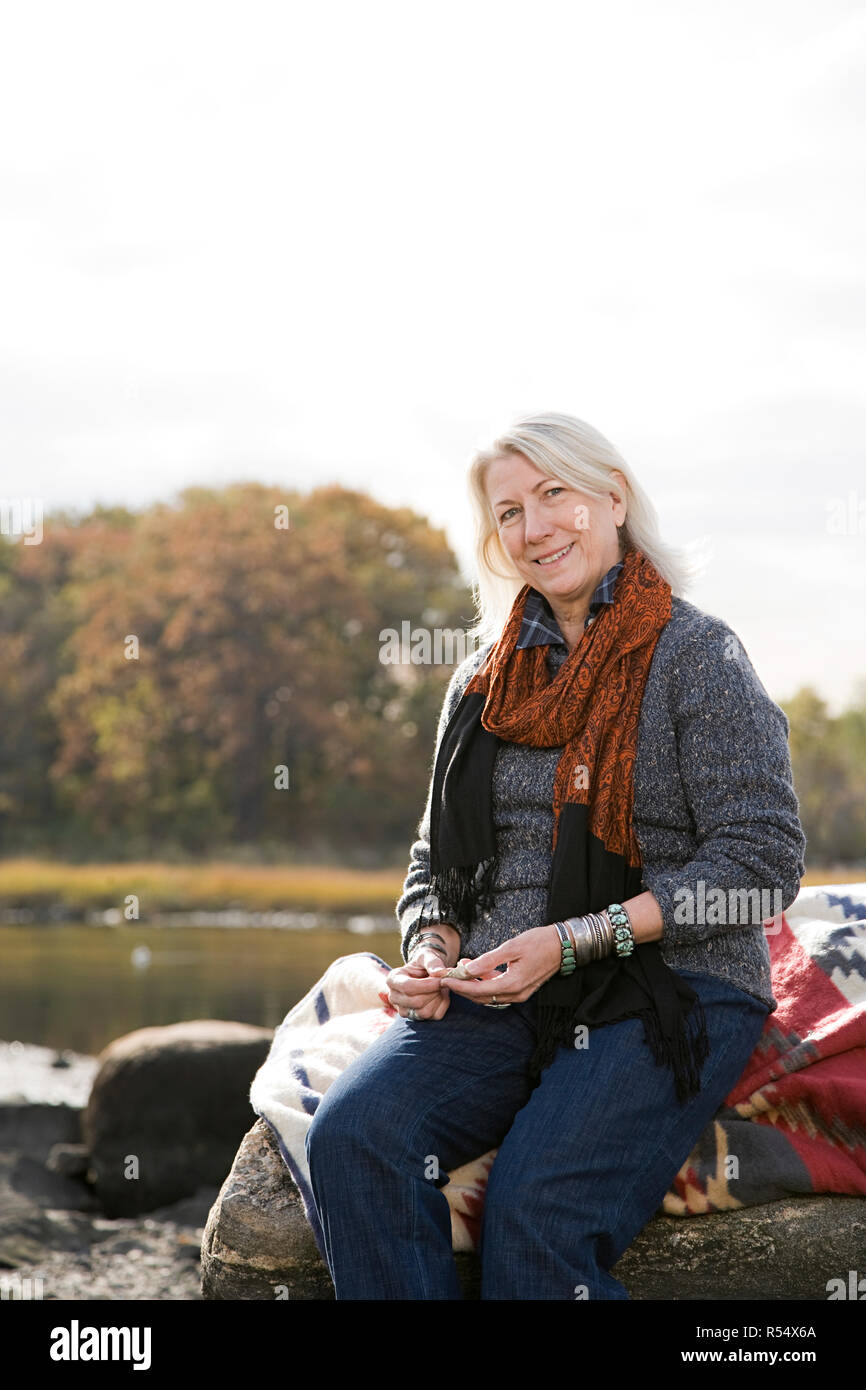 Senior woman sitting on rocks Stock Photo - Alamy