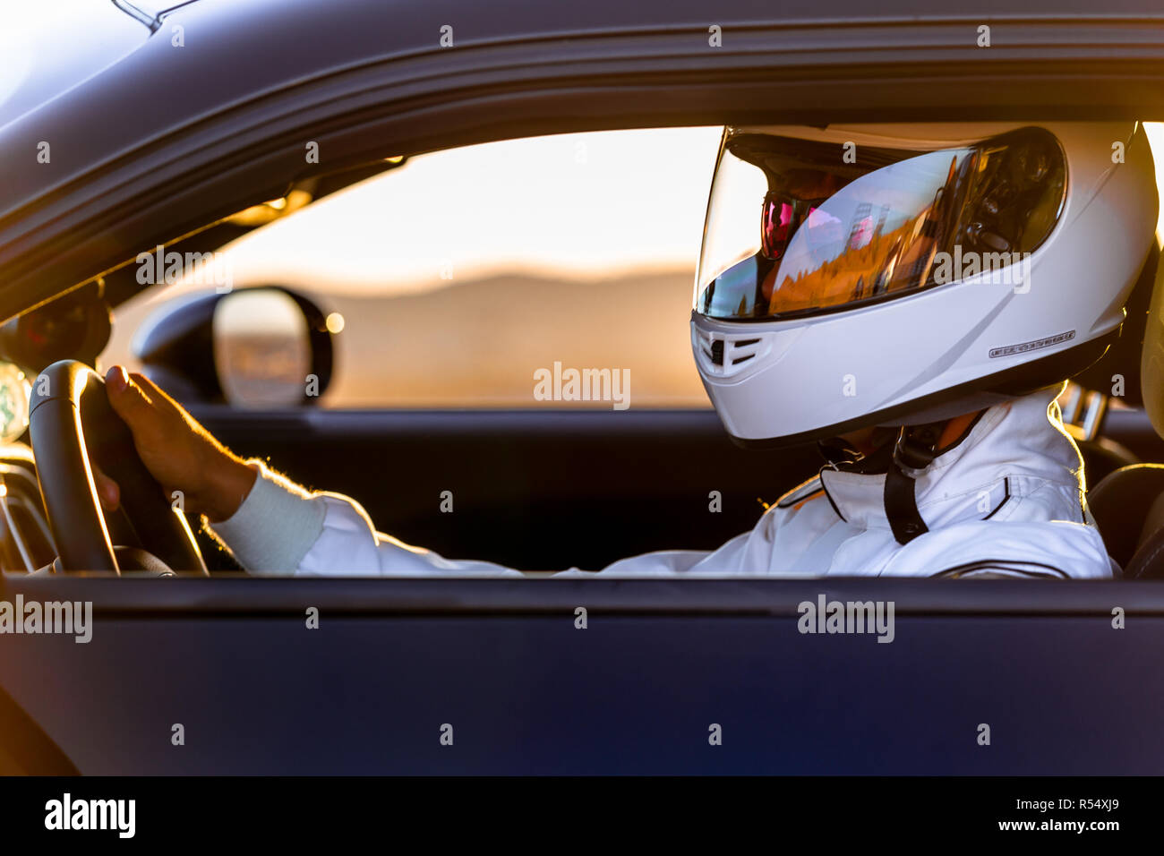 A race car driver wearing a helmet at the wheel of his vehicle on a ...