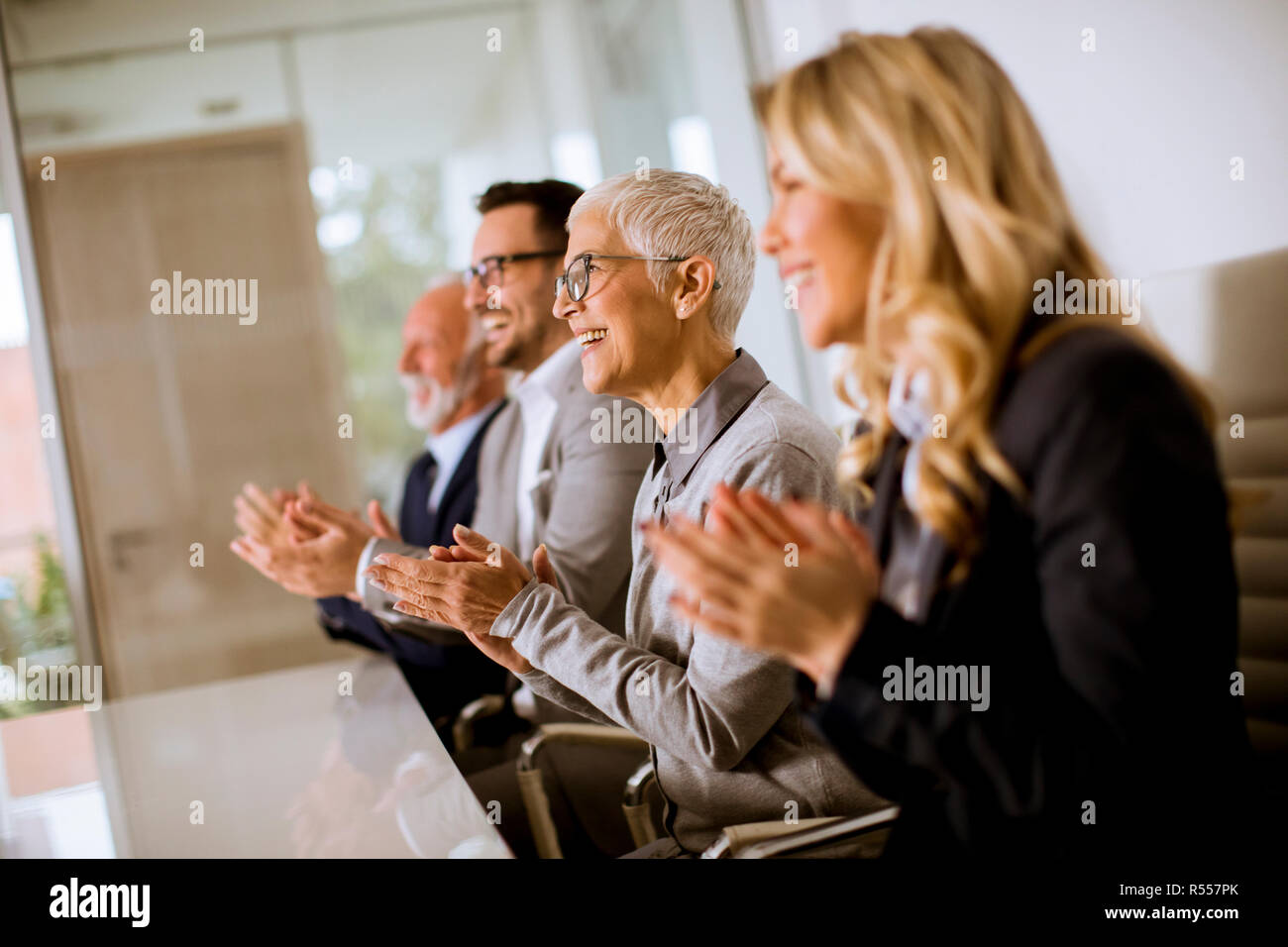 Satisfied proud business team clapping hands while sitting in row at ...