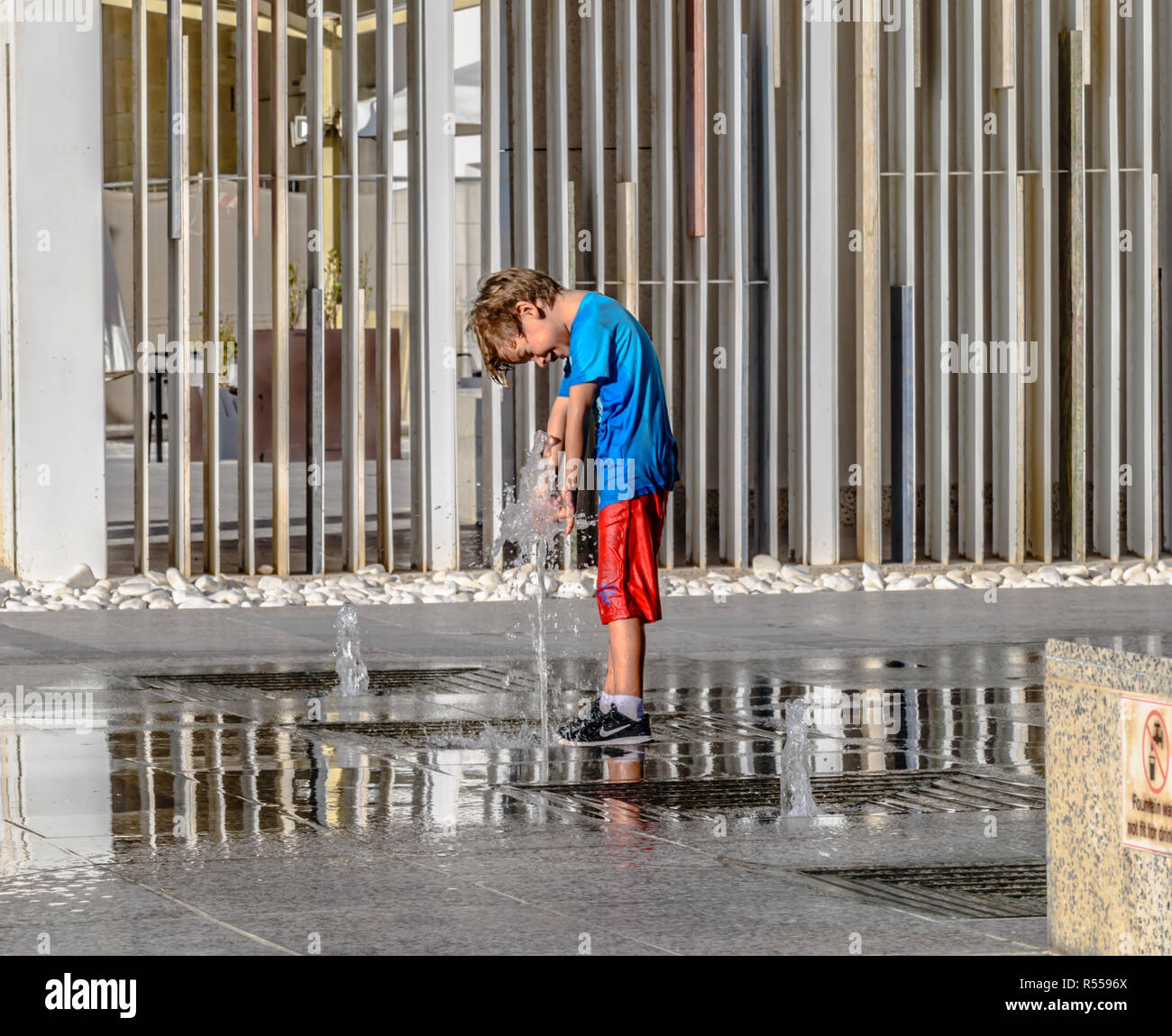 Boy playing with water fountain Stock Photo - Alamy