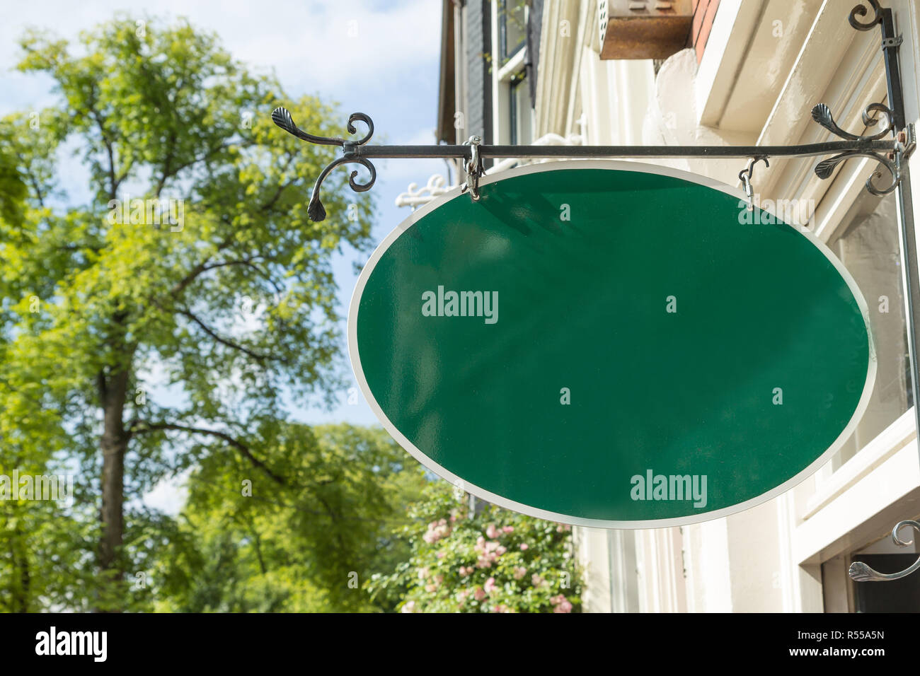 Old style wrought green iron hanging shop sign house Stock Photo - Alamy