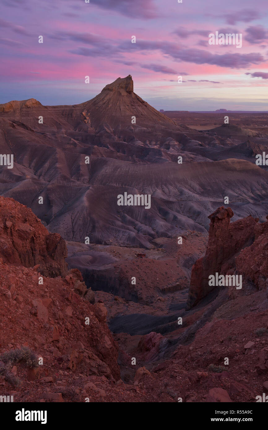A draw looks down on a hoodoo, sand dunes, and a bluff at sunset in the ...