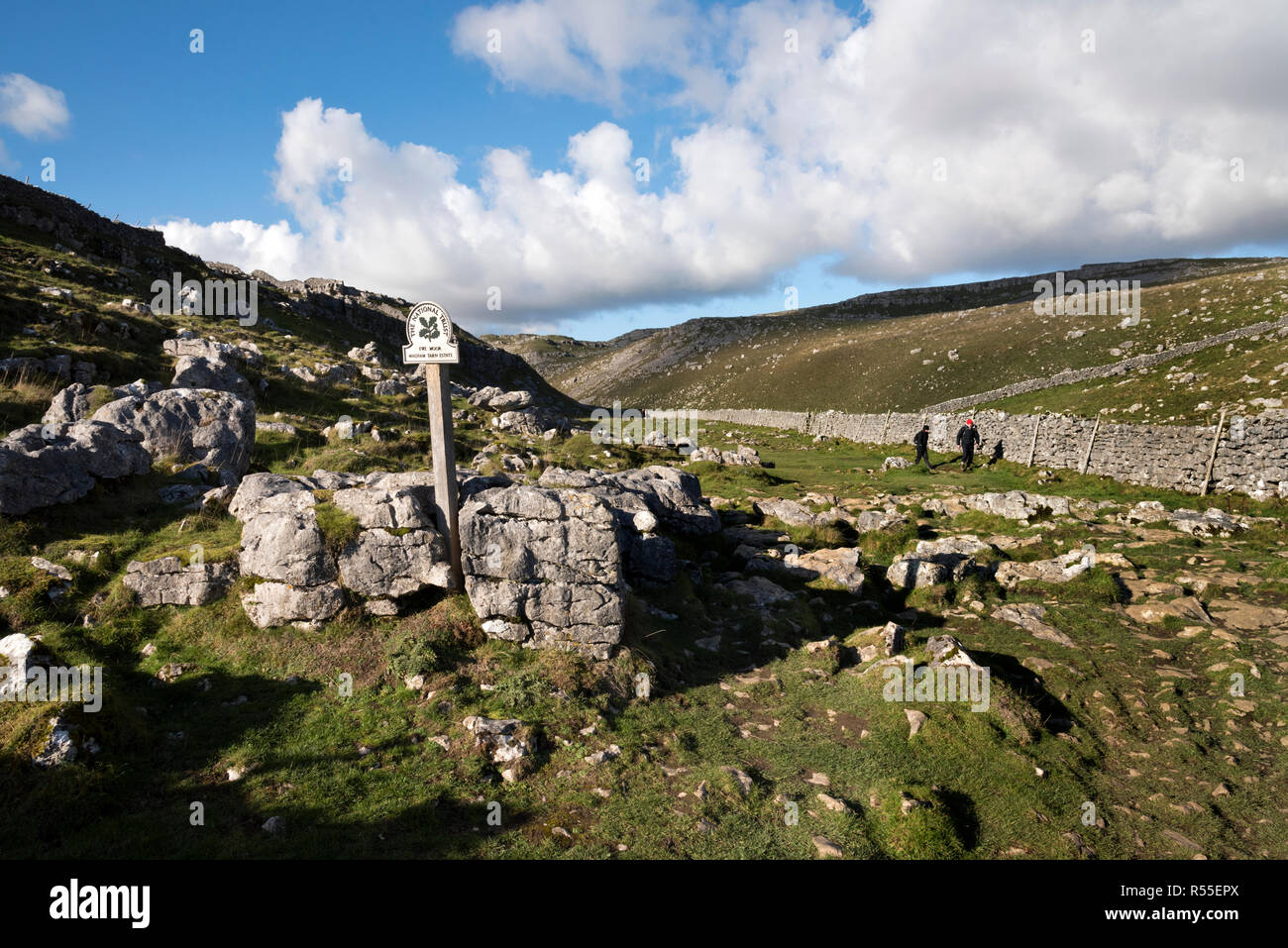 Walkers in the limestone rock valley above Malham Cove, Yorkshire ...