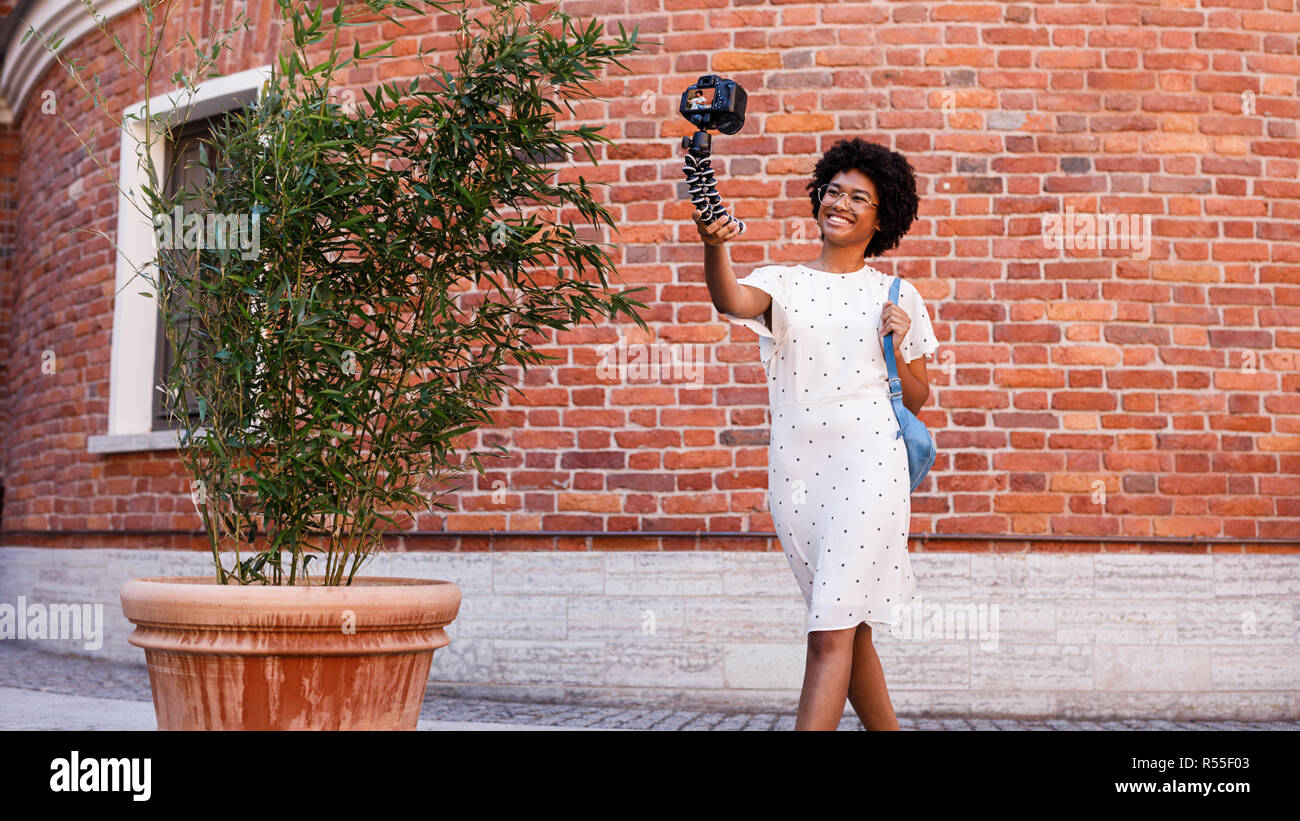Young female vlogger filming a video while walking on city street Stock ...