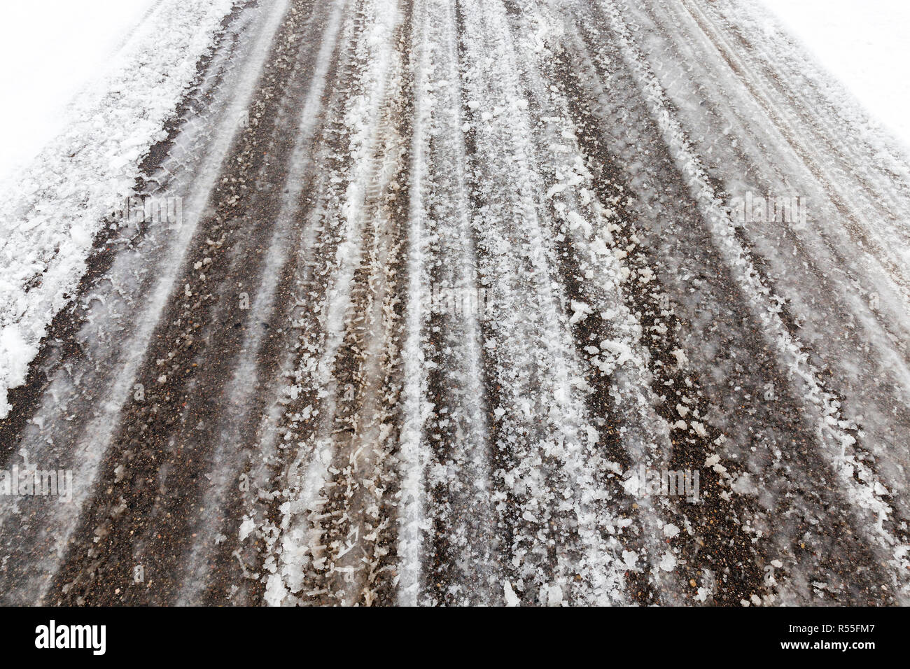 photo of tracks on a road covered with snow falling during a snowfall ...