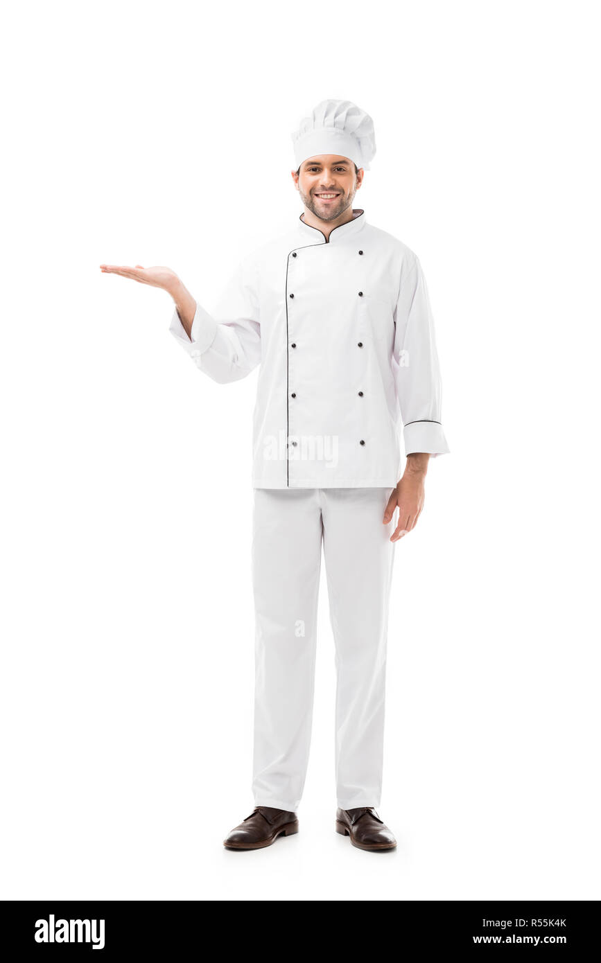 smiling young chef pointing at blank space and looking at camera ...