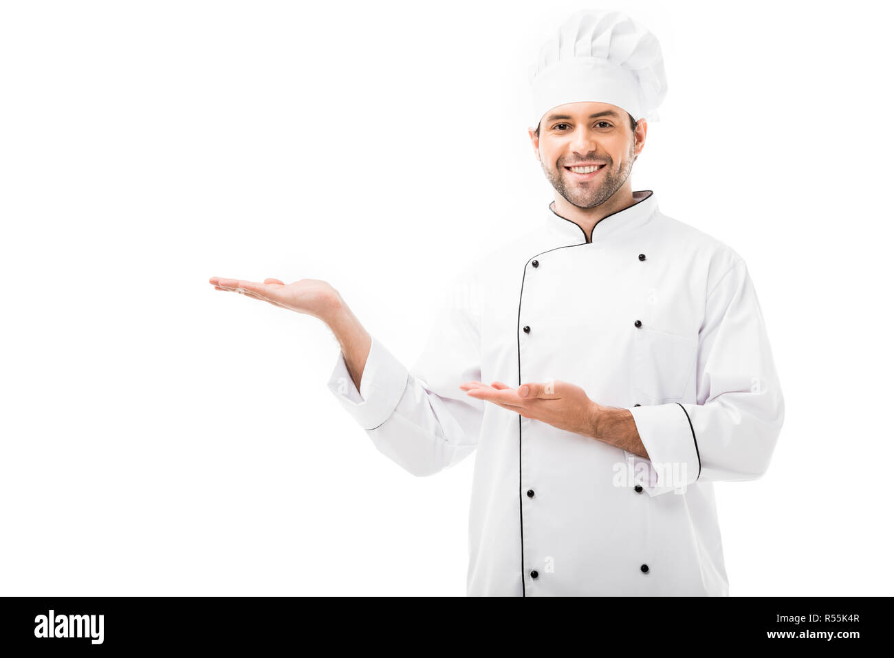happy young chef pointing at blank space and looking at camera isolated ...