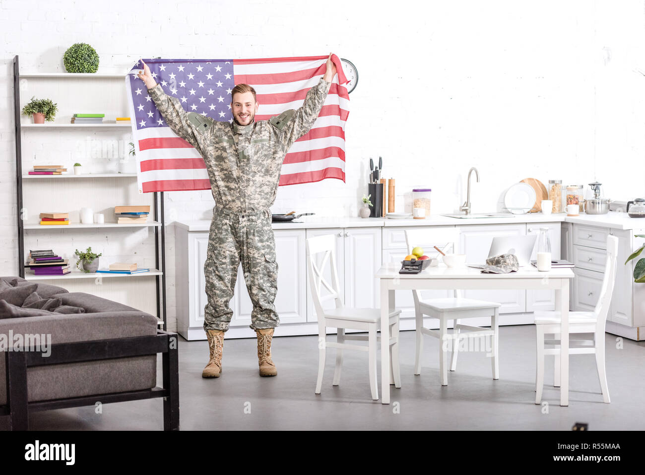 smiling army soldier standing, looking at camera and proudly holding ...