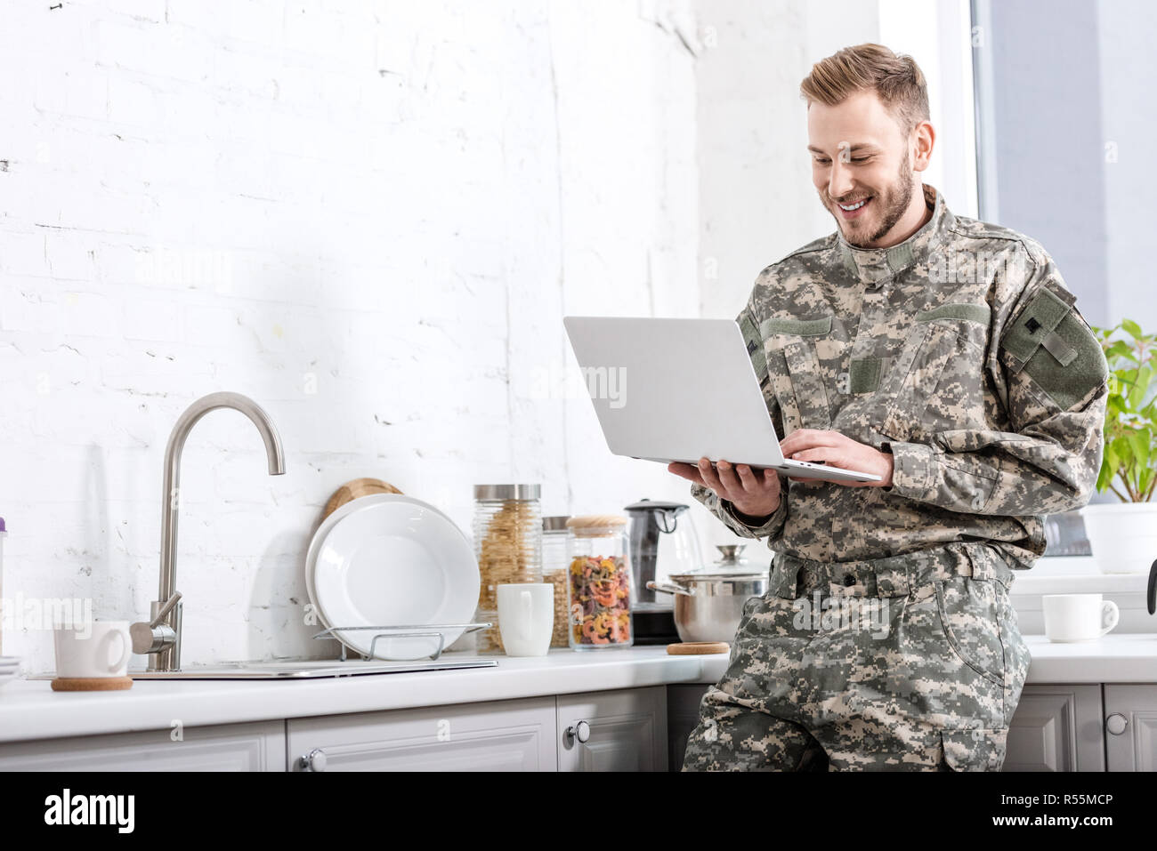 handsome army soldier in uniform using laptop at kitchen Stock Photo ...