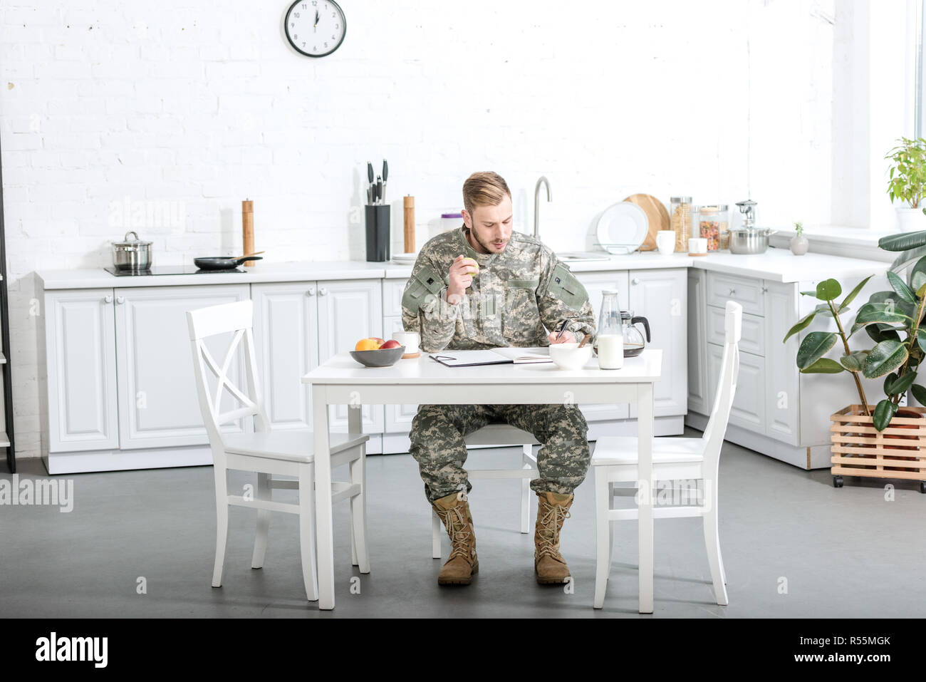 army soldier sitting at kitchen table and having breakfast at home ...