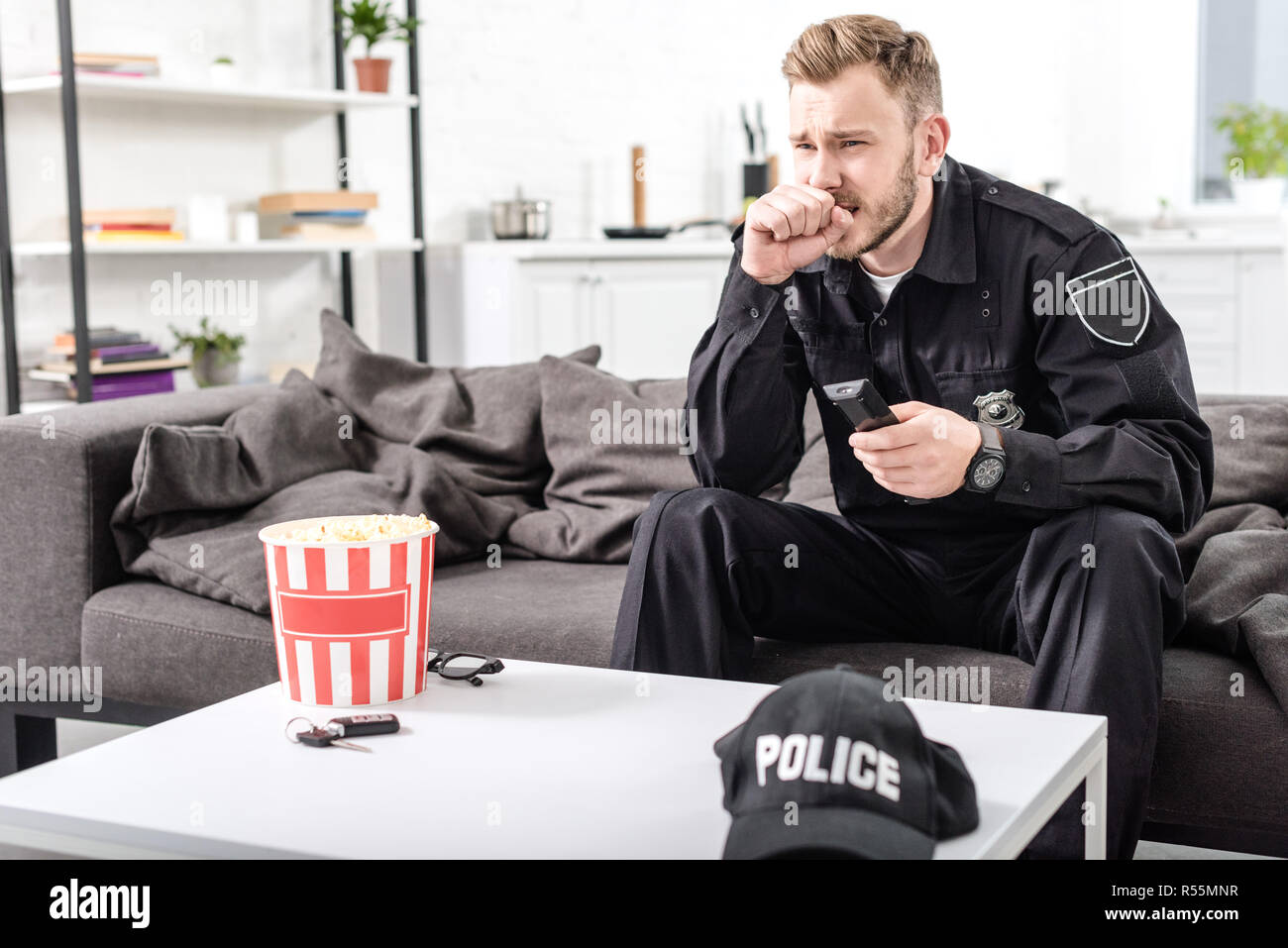 policeman with scared face expression sitting on couch and watching ...