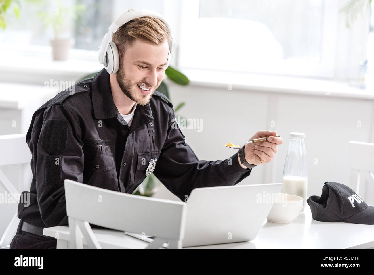 Handsome police officer having breakfast and listening to music with ...