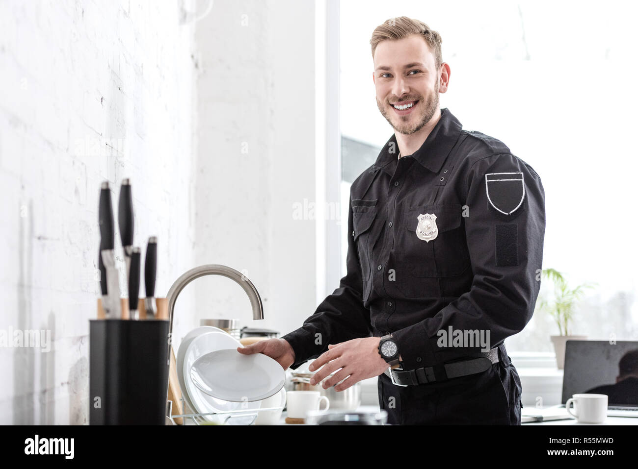 Handsome police officer washing dishes at kitchen Stock Photo - Alamy