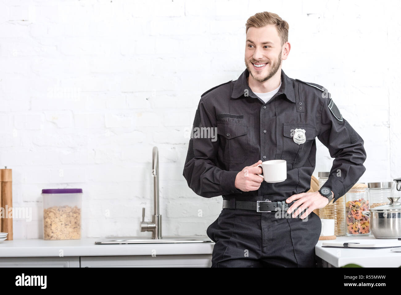 Handsome police officer drinking coffee at kitchen Stock Photo - Alamy