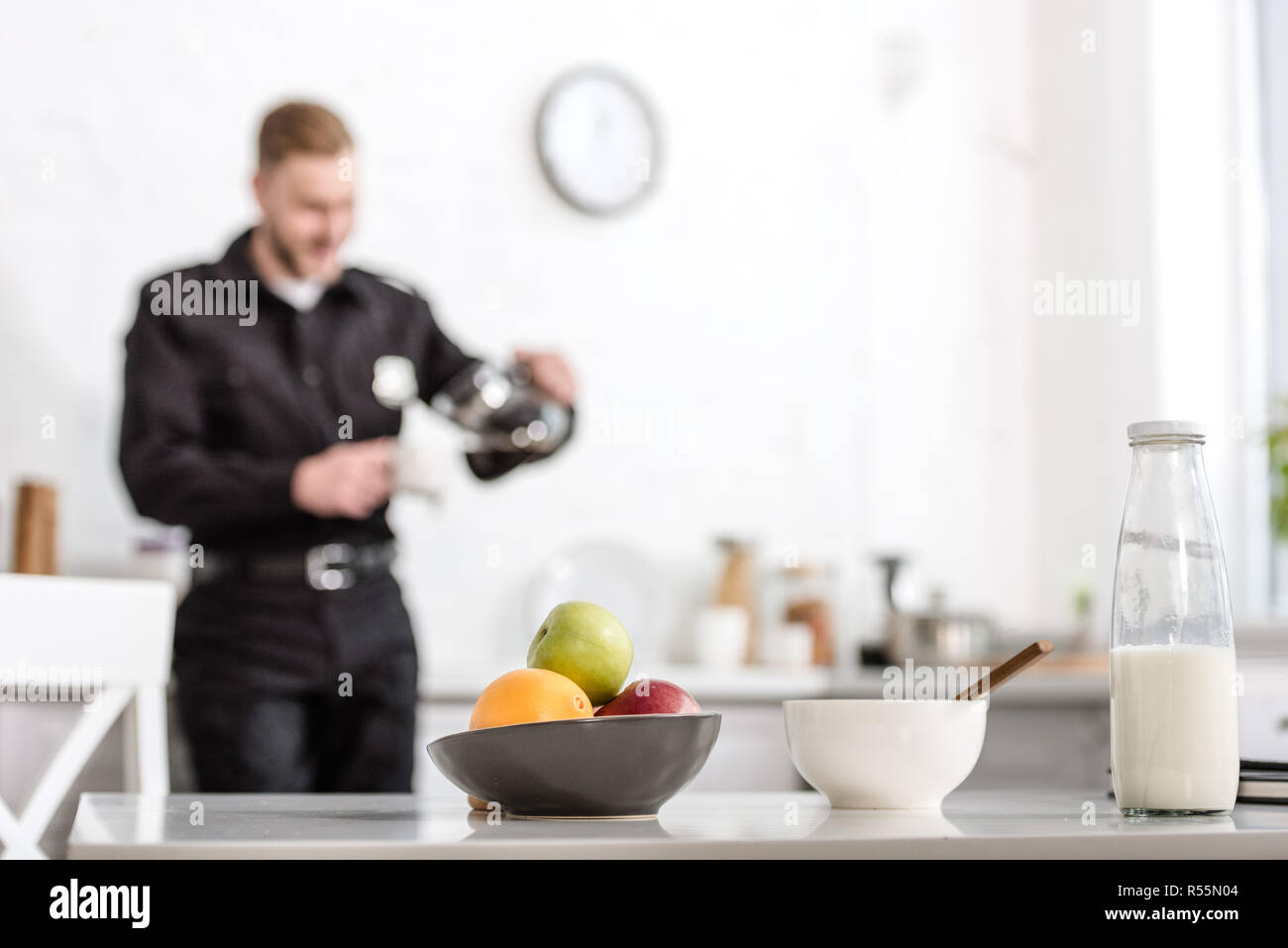 milk bottle, bowl of fruits on kitchen table and police officer at ...