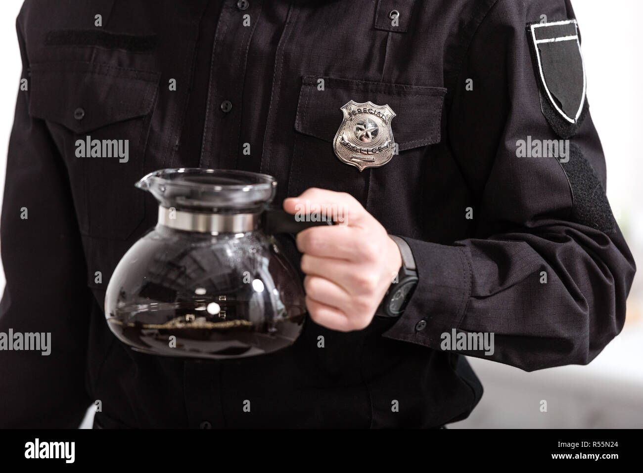 cropped view of police officer holding glass pot of hot filtered coffee ...