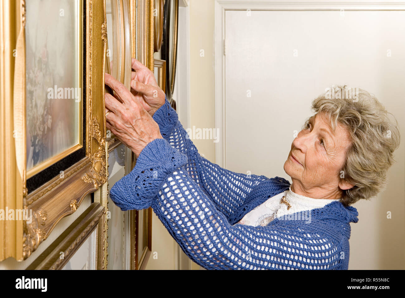 Woman adjusting picture frames Stock Photo - Alamy