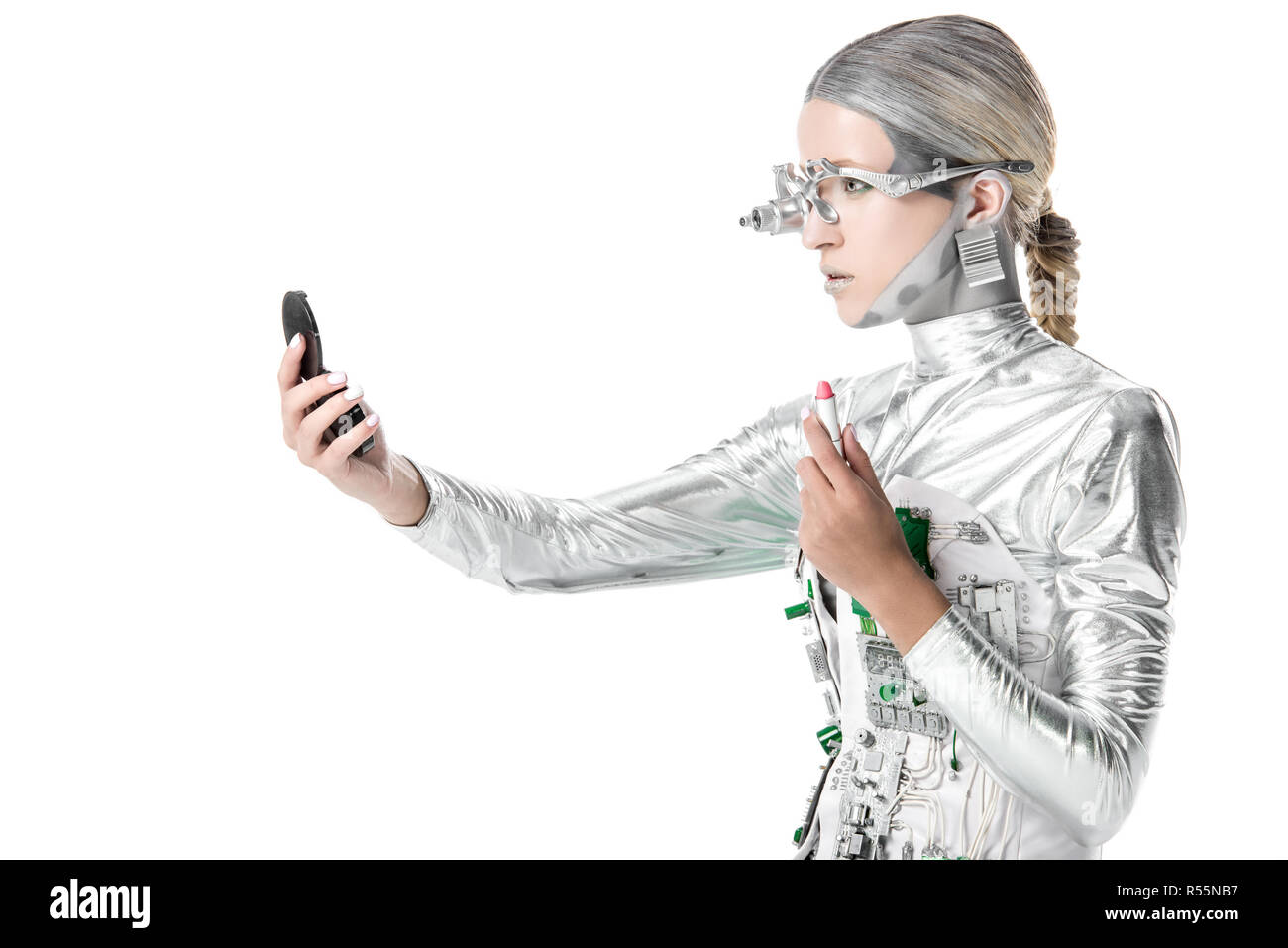 side view of silver robot holding lipstick and looking at mirror ...