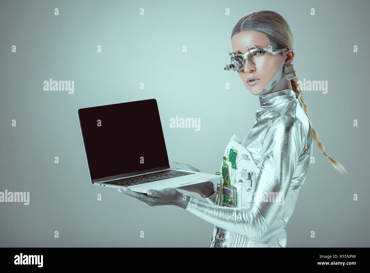 silver robot holding laptop with blank screen isolated on grey, future ...