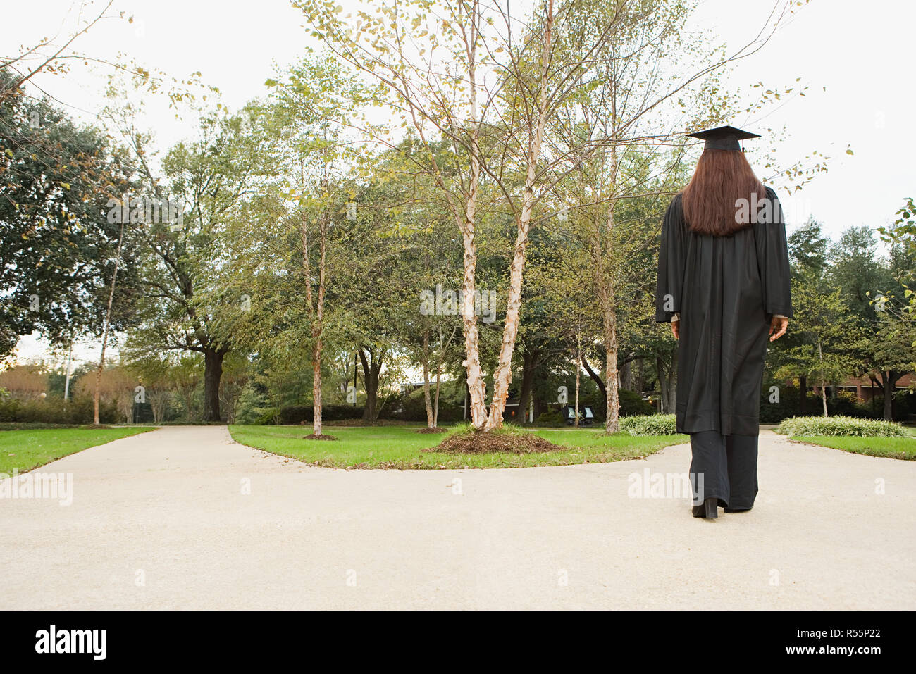 Female graduate walking down a path Stock Photo - Alamy