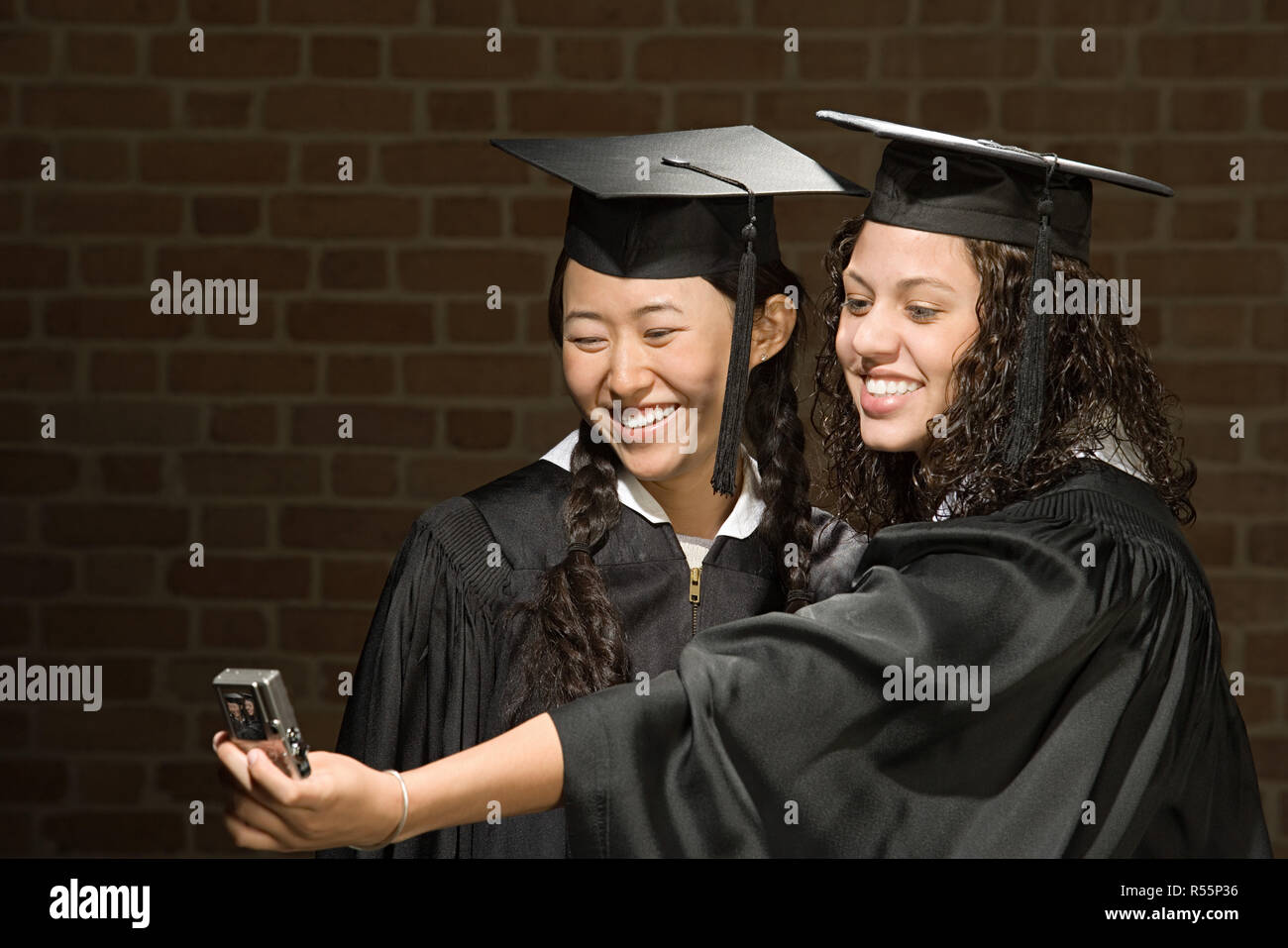 Two female graduates taking a photograph Stock Photo - Alamy