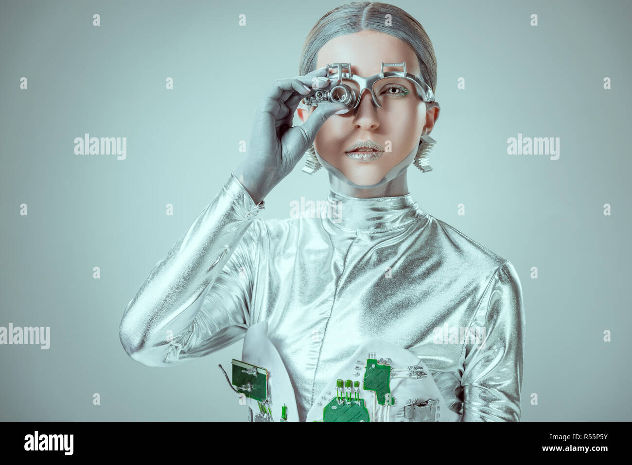 futuristic silver robot adjusting eye prosthesis and looking at camera ...