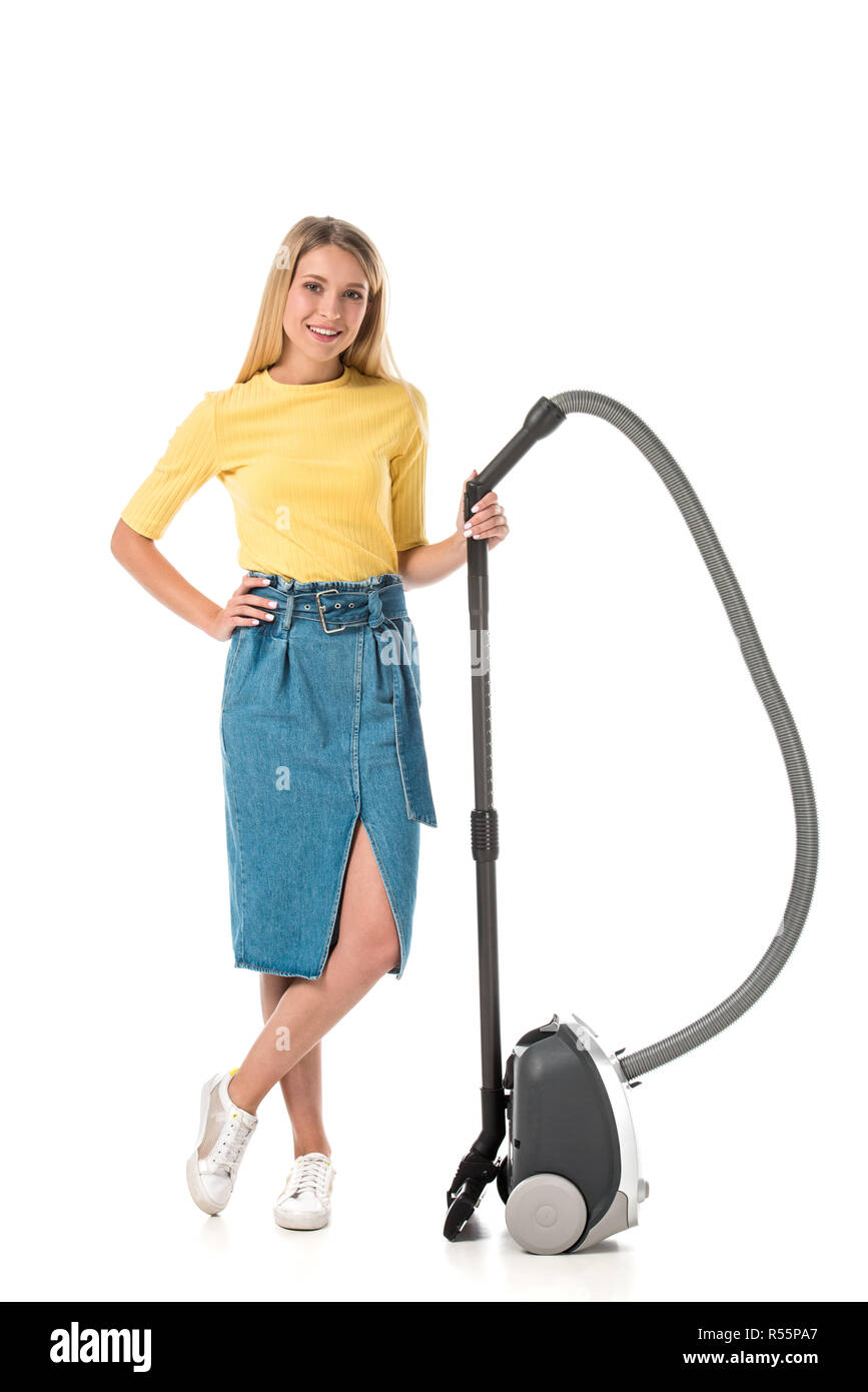 attractive young woman standing with vacuum cleaner and smiling at ...