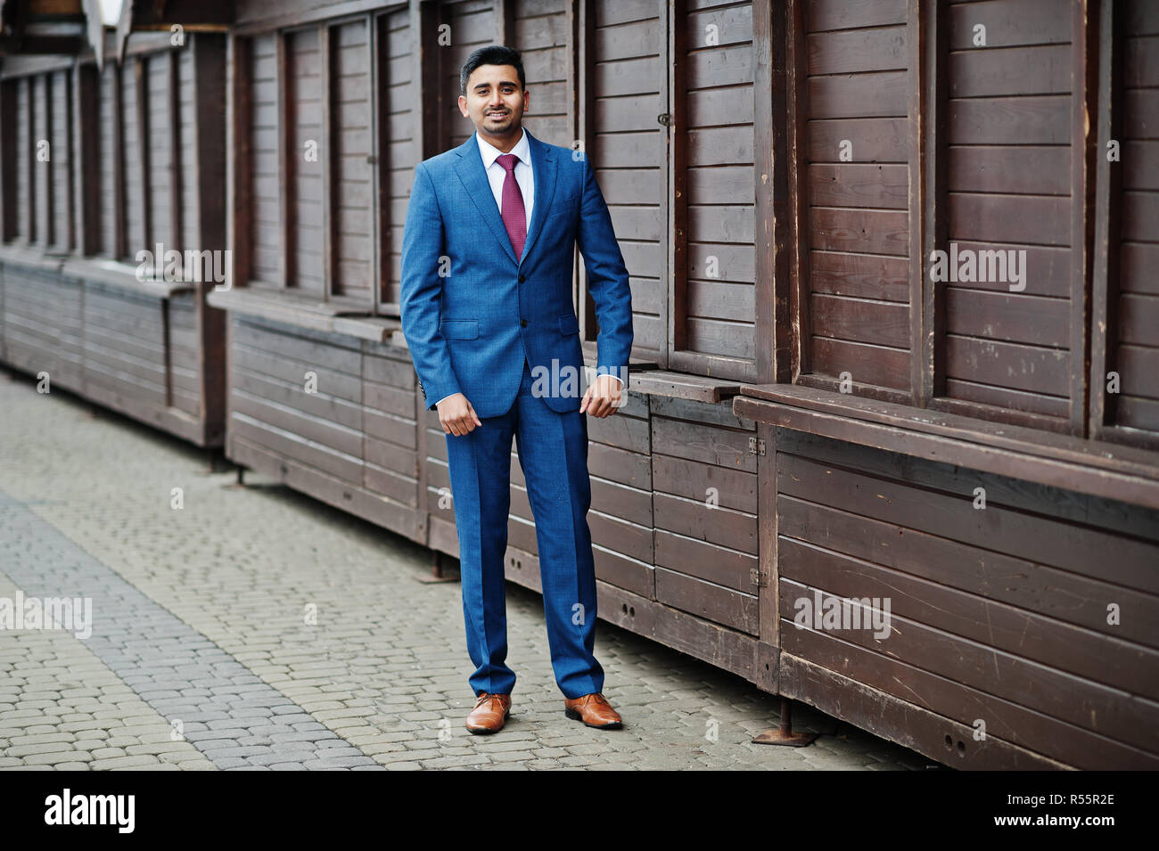 Elegant indian fashionable man model on suit posed against wooden ...