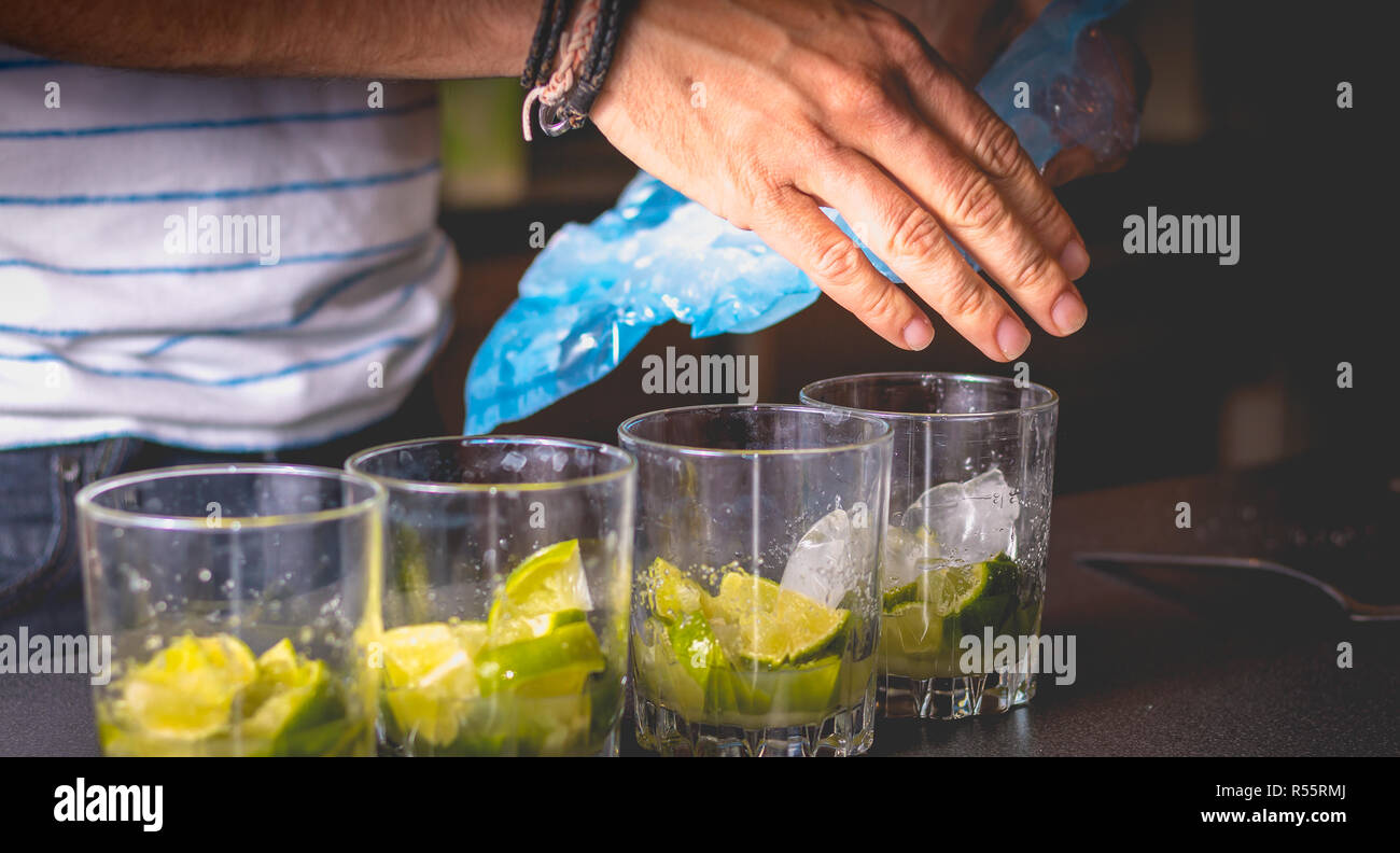 bartender puts ice cubes in glasses of brezillian caipirinha Stock Photo - Alamy