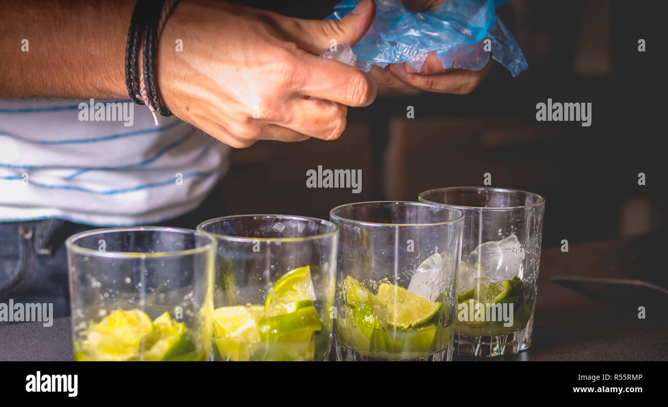bartender puts ice cubes in glasses of brezillian caipirinha Stock Photo - Alamy