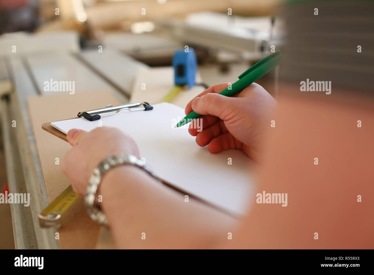 Arms of worker making notes on clipboard with green pen Stock Photo - Alamy