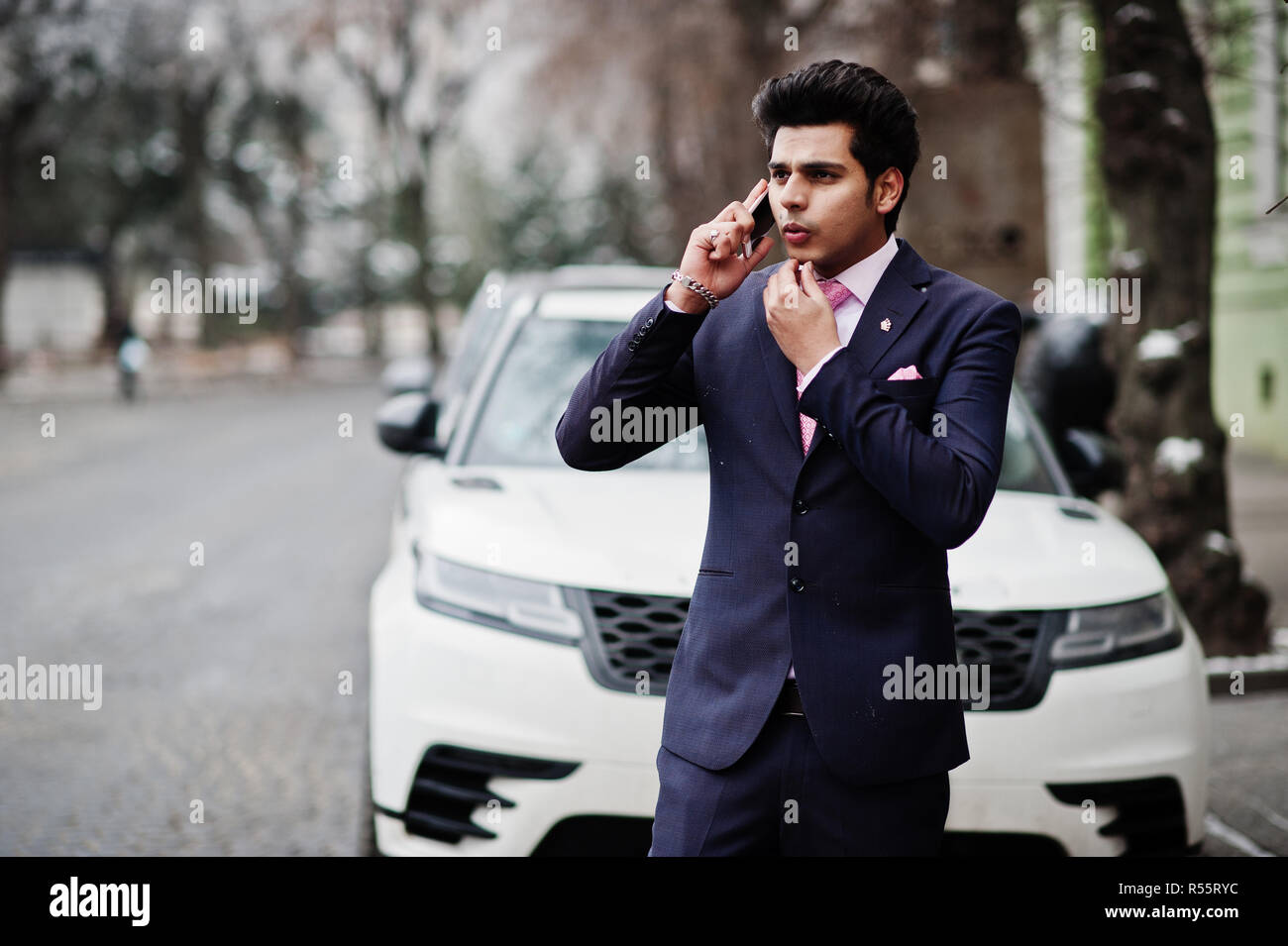 Elegant indian macho man model on suit and pink tie posed against white ...