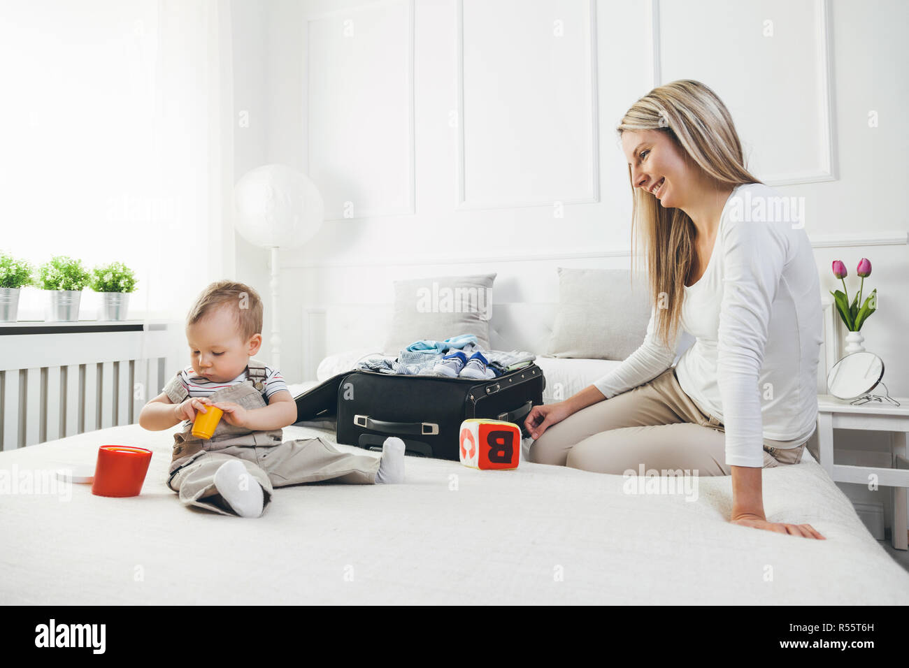 Travelling with kids. Happy mother with her child packing clothes for ...