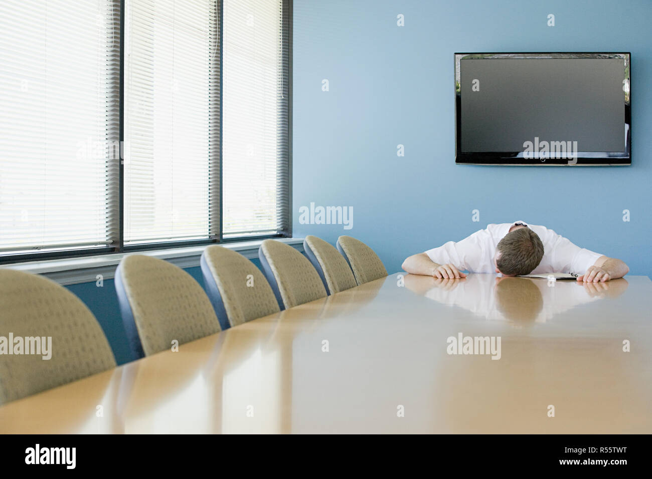 Man sleeping on conference table Stock Photo - Alamy
