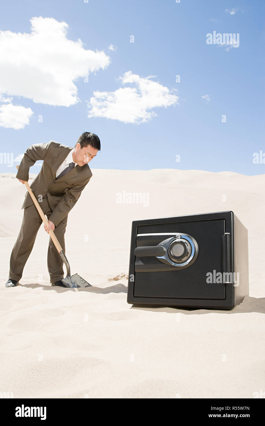 Man digging by safe in desert Stock Photo - Alamy