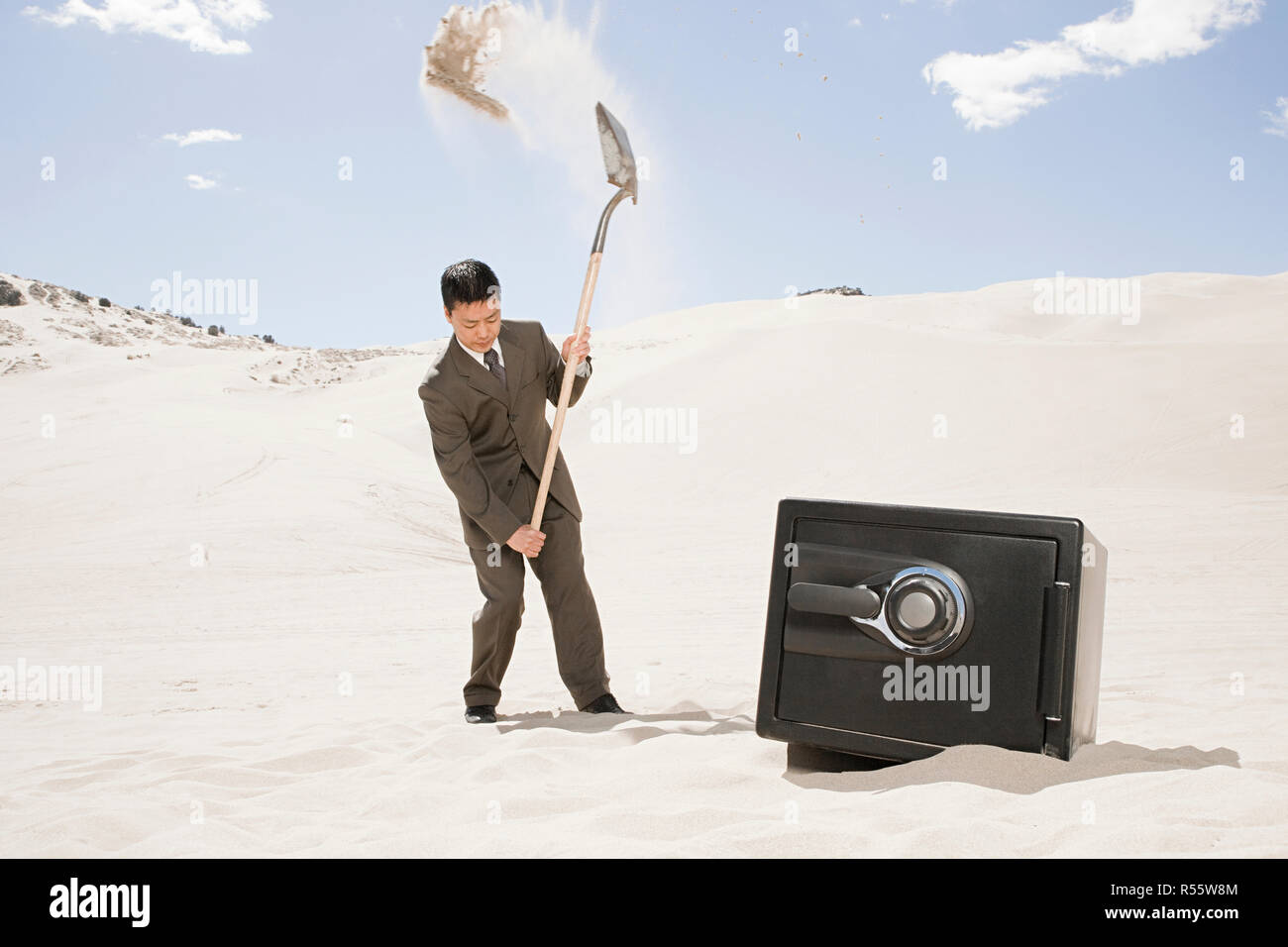 Man digging by safe in desert Stock Photo - Alamy