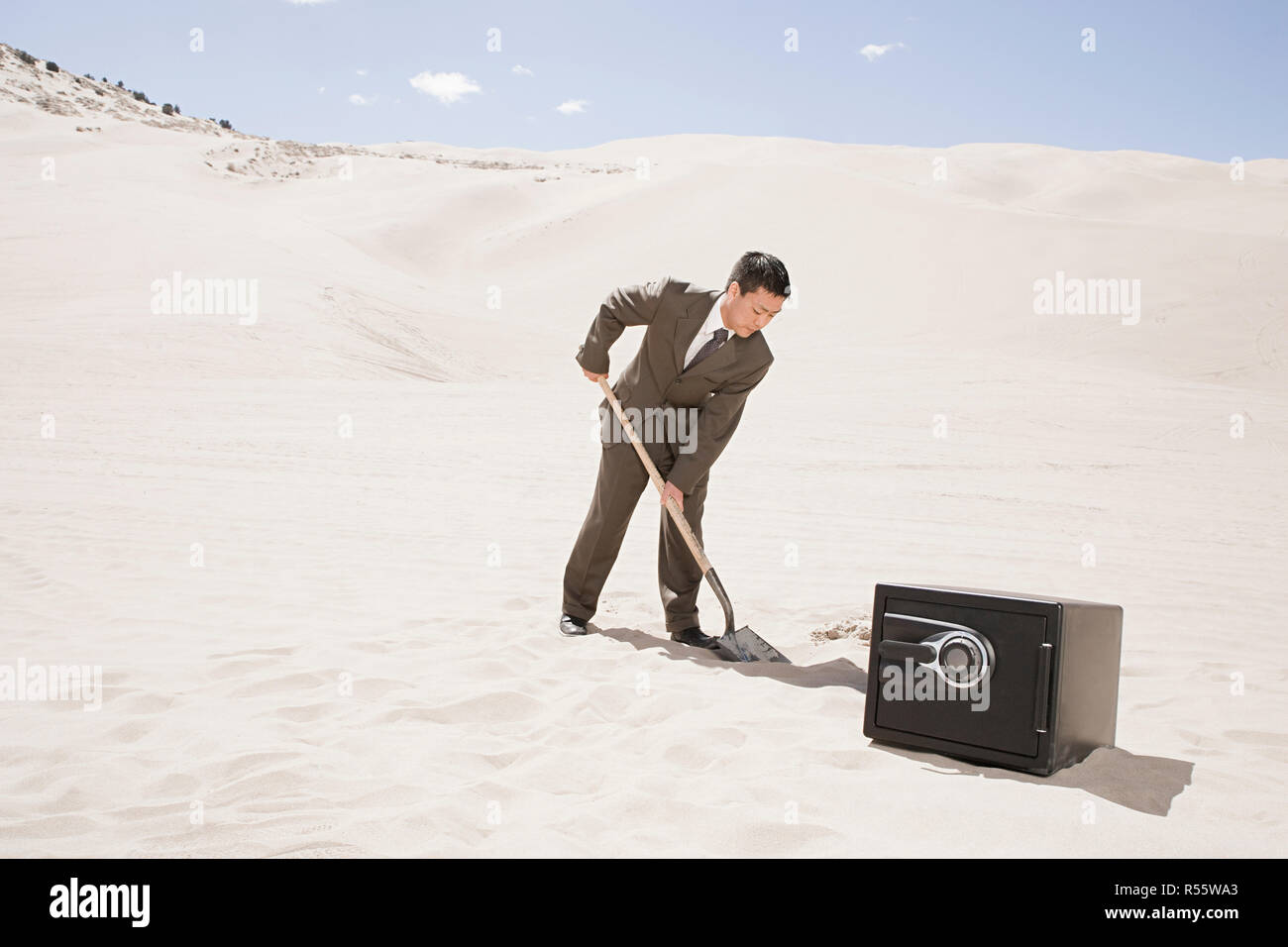 Man digging by safe in desert Stock Photo - Alamy