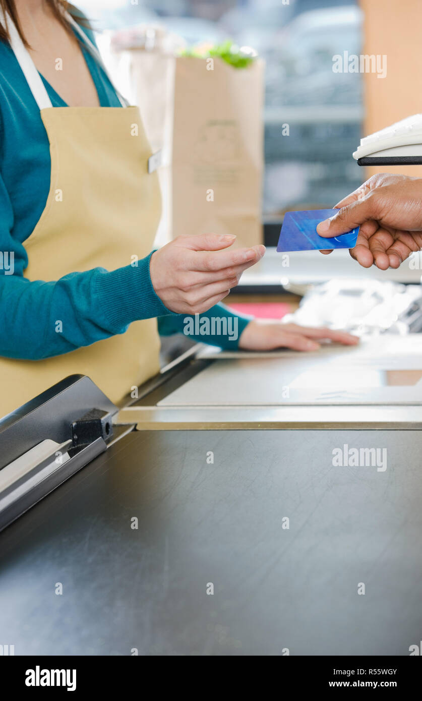 Customer handing a sales assistant a credit card Stock Photo - Alamy