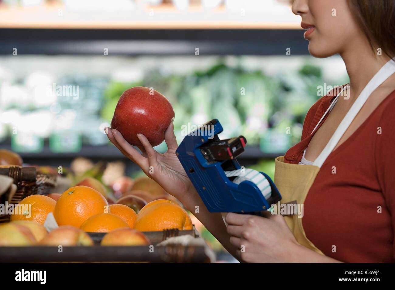sales assistant pricing an orange Stock Photo - Alamy
