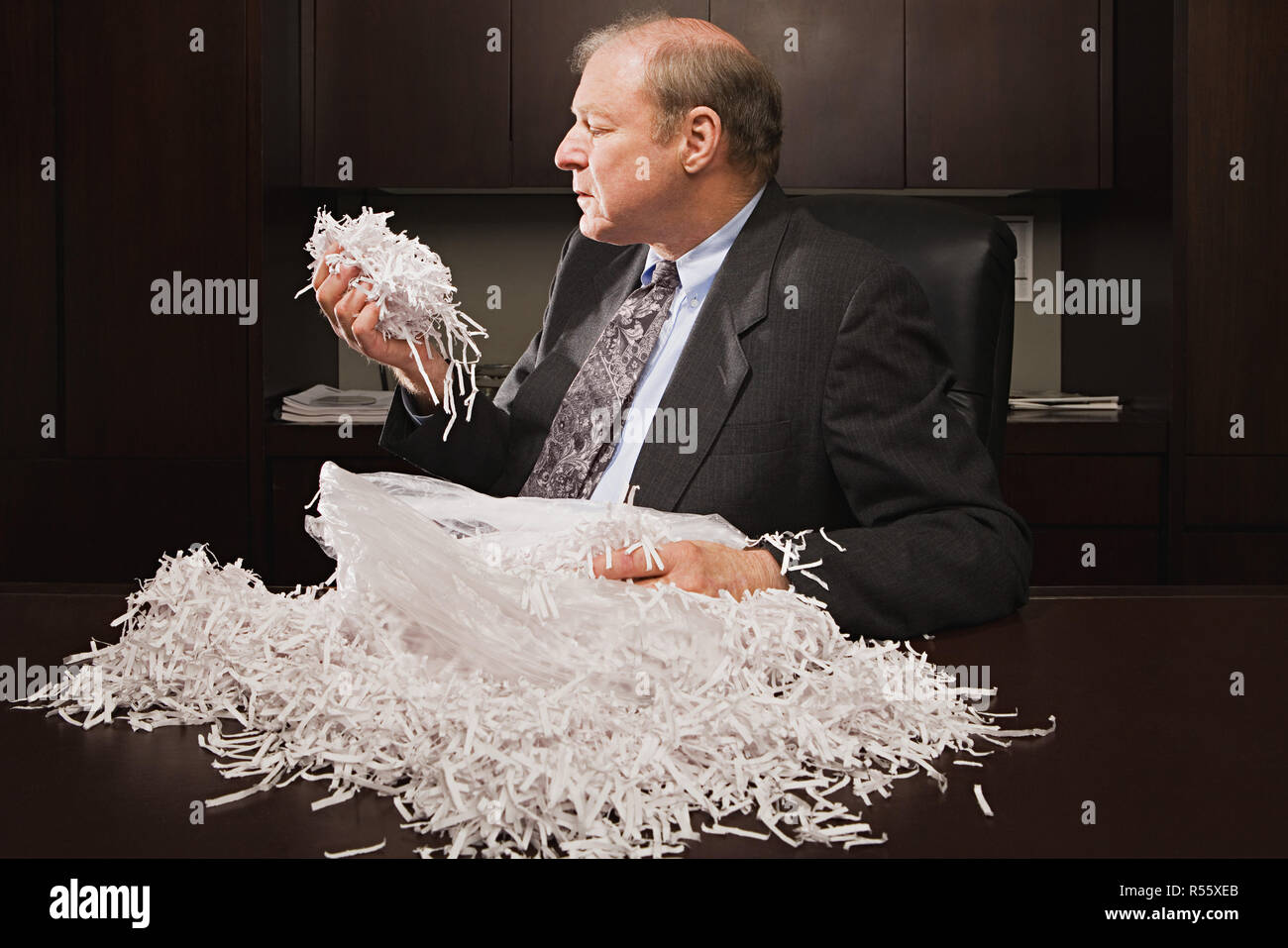 Mature businessman playing with paper shreddings Stock Photo - Alamy