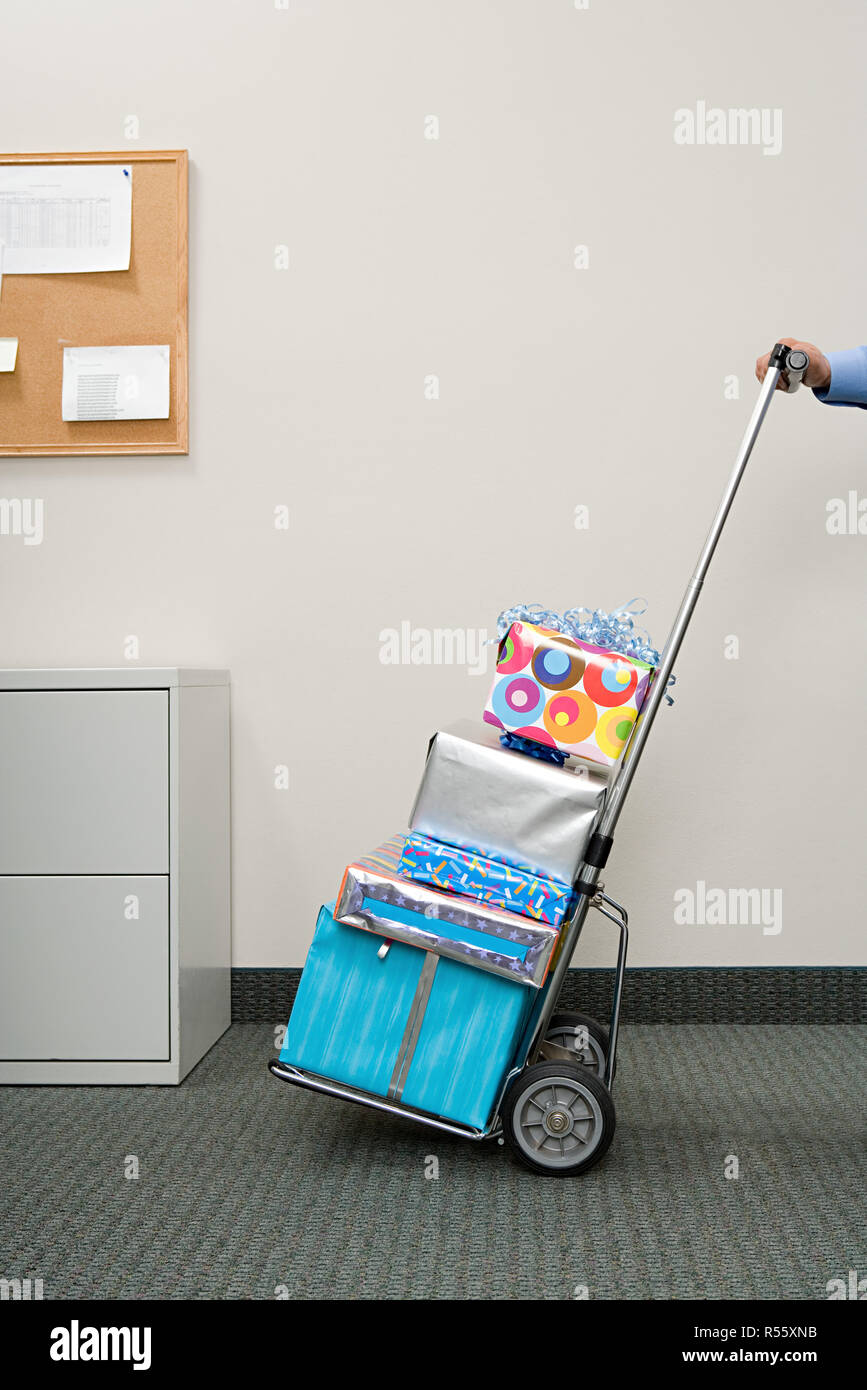 Man pushing trolley of presents Stock Photo - Alamy
