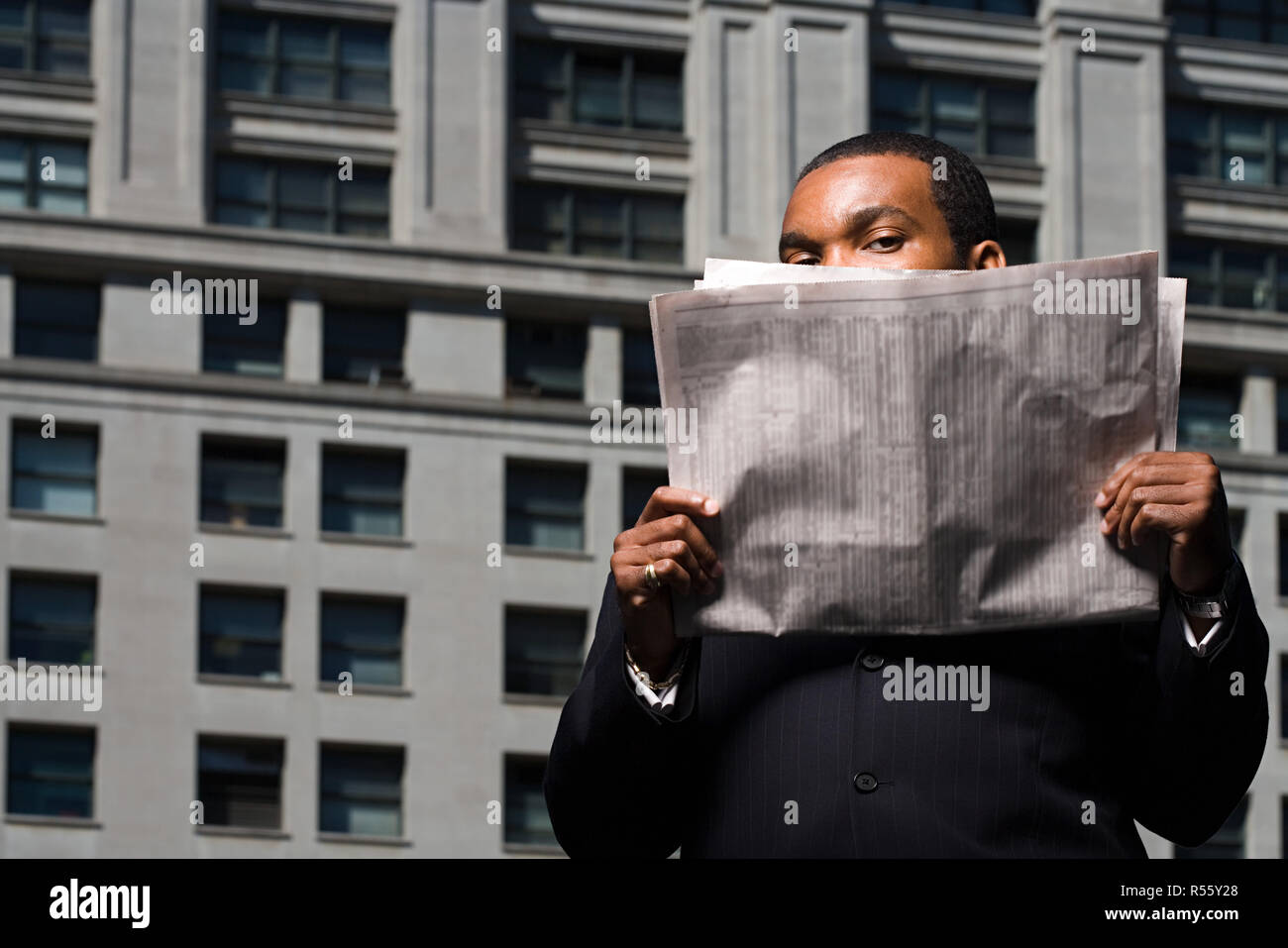 Businessman looking over newspaper Stock Photo - Alamy