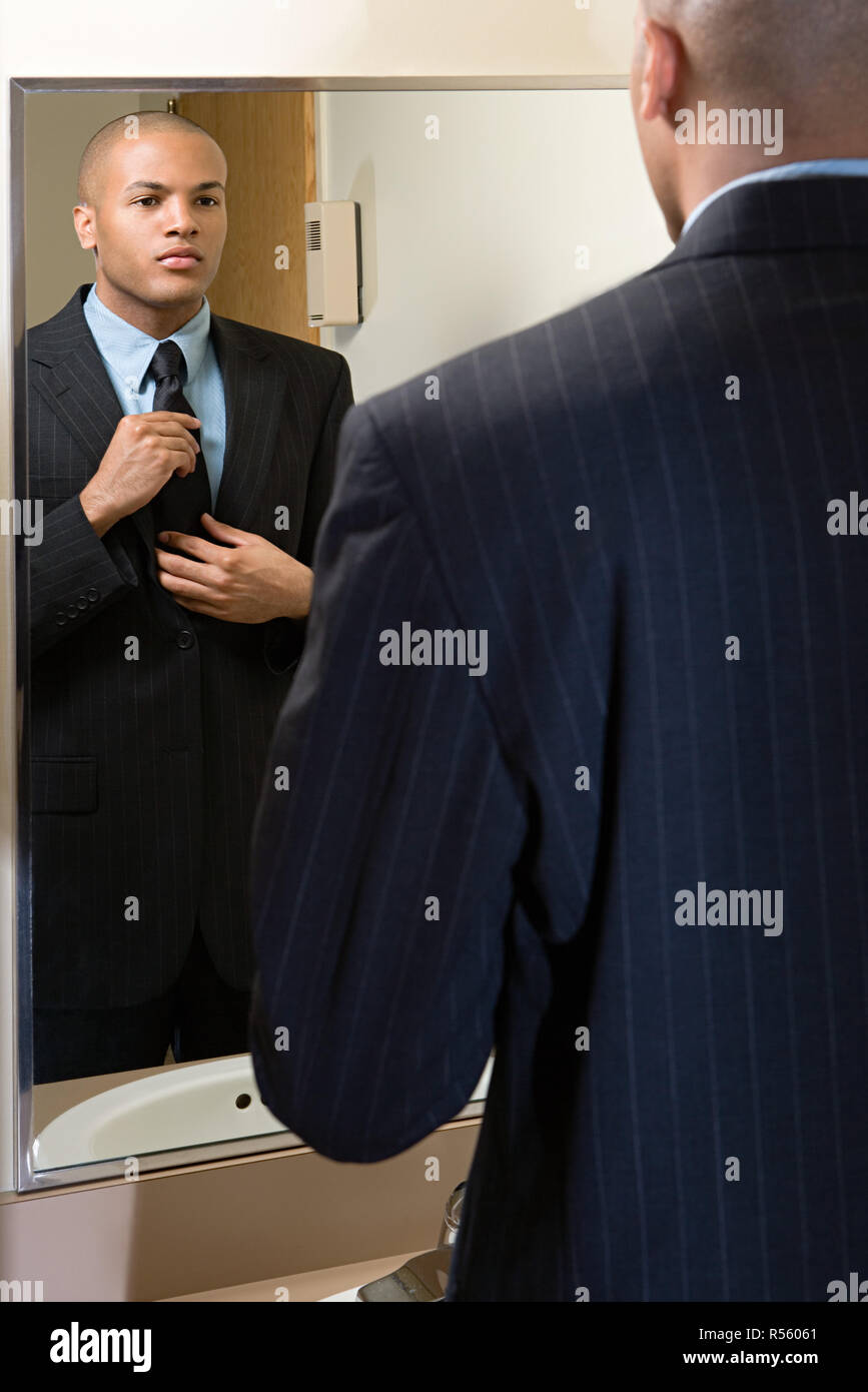 Man adjusting his tie in mirror Stock Photo - Alamy