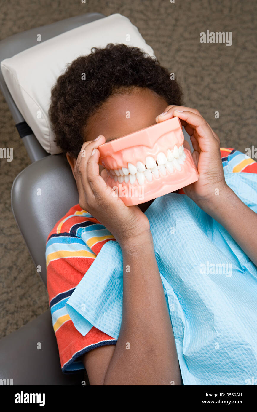 Boy covering face with false teeth Stock Photo - Alamy