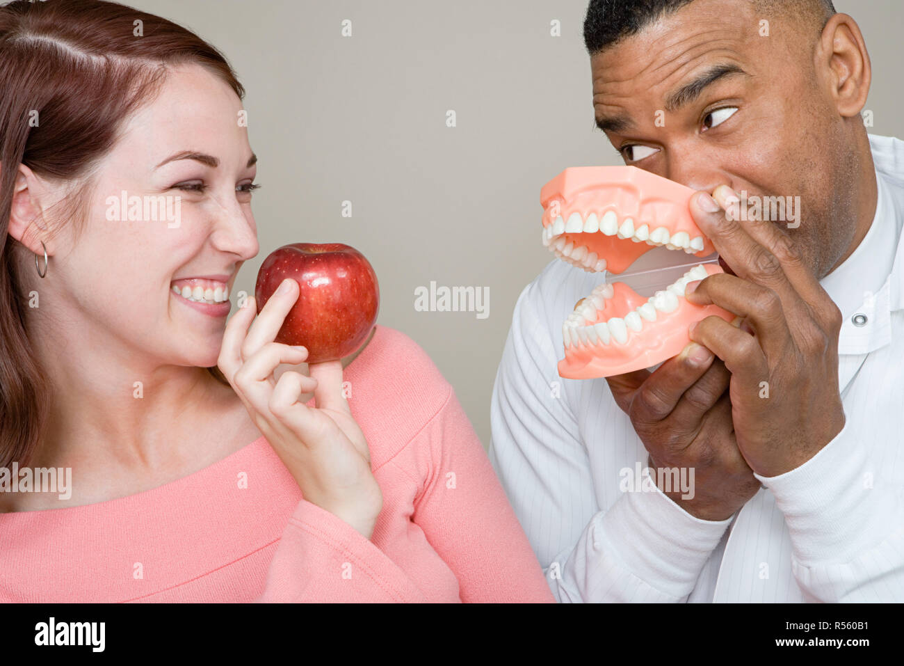 Dentist and woman holding an apple and false teeth Stock Photo - Alamy