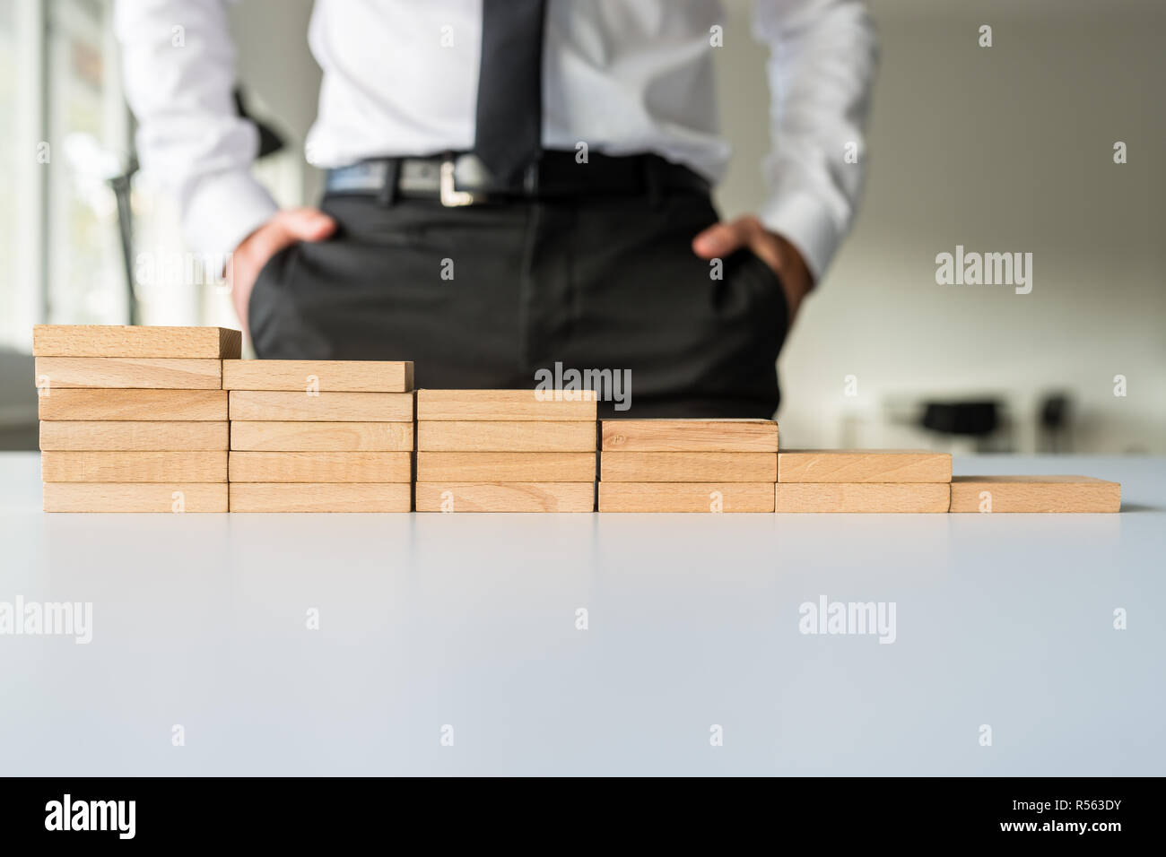 Staircase made of wooden pegs on office desk with business executive ...