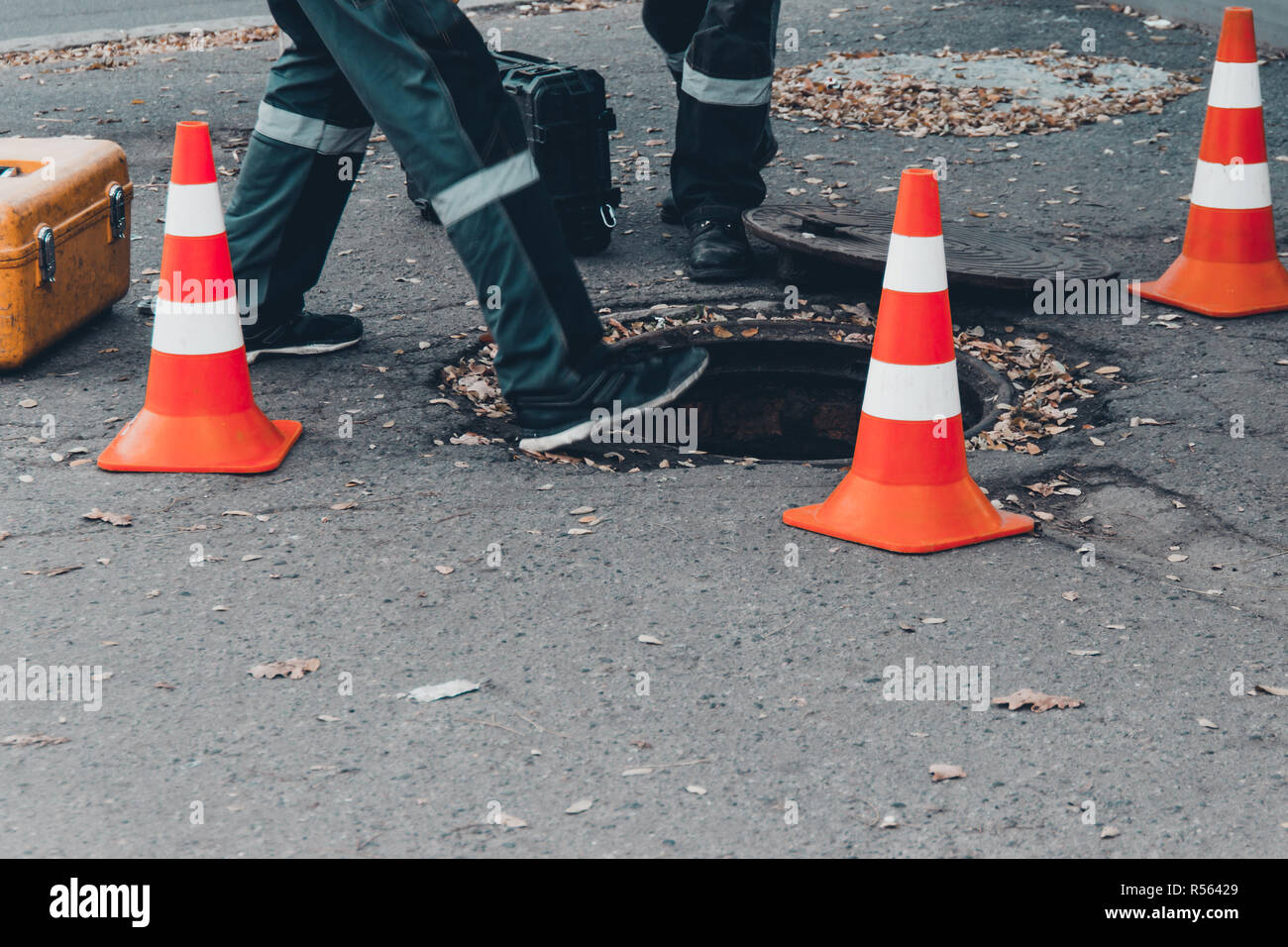 Employees of a telephone company near an open underground hatch ...