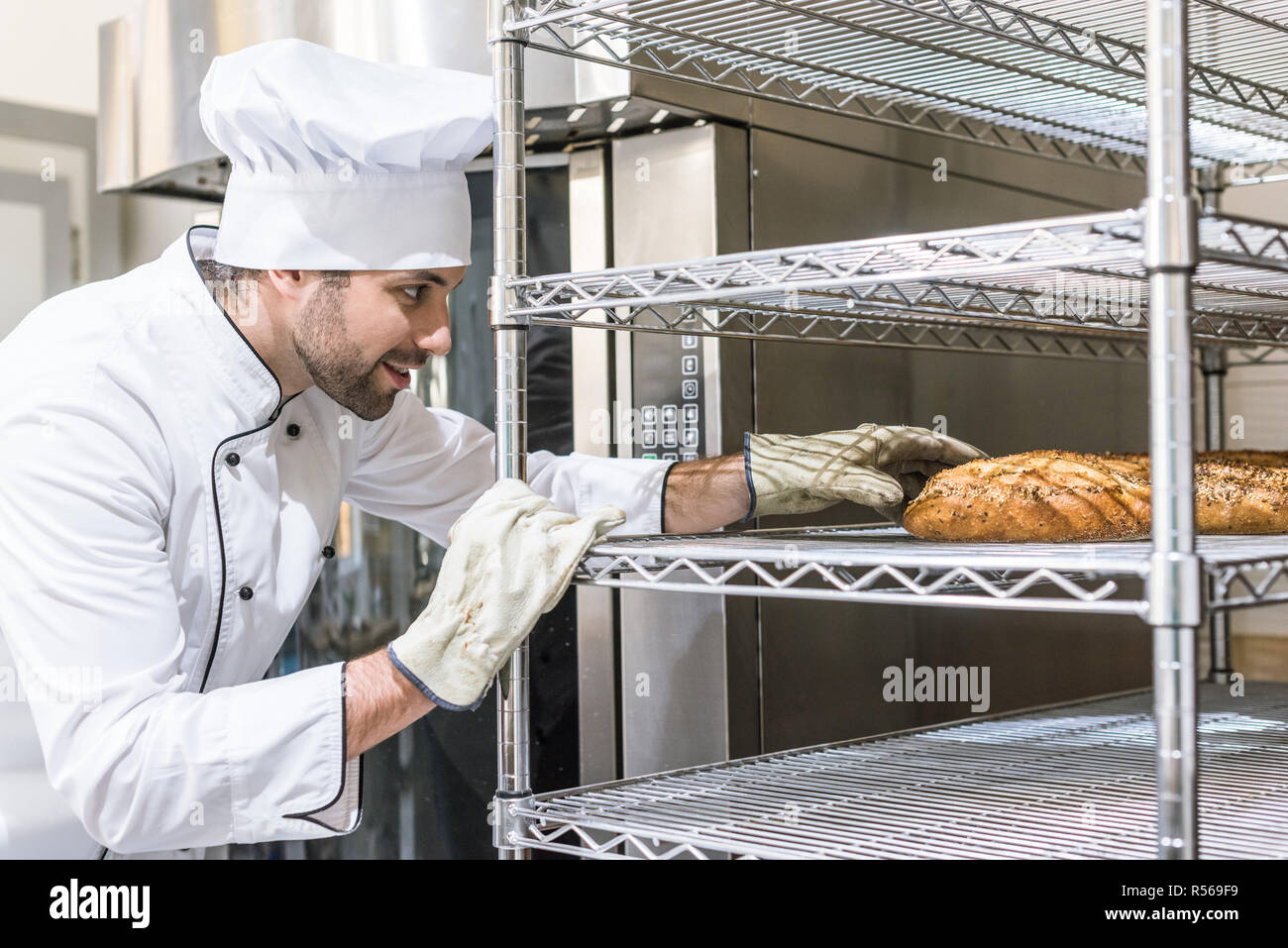 Side view of baker in gloves taking bread Stock Photo - Alamy