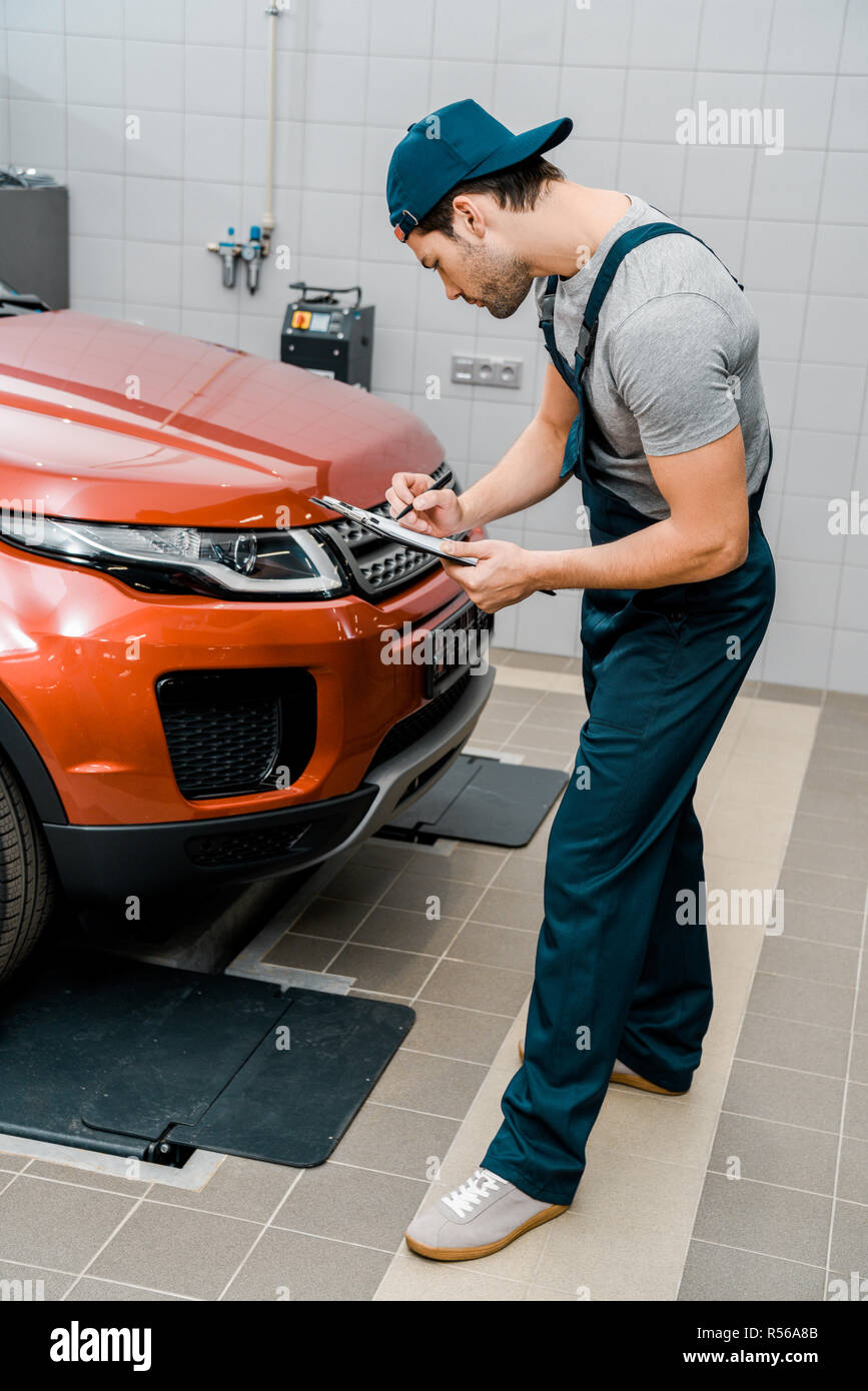 auto mechanic with notepad examining car at auto repair shop Stock ...