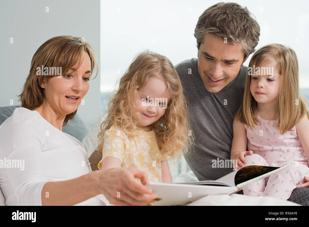 family reading a book Stock Photo - Alamy